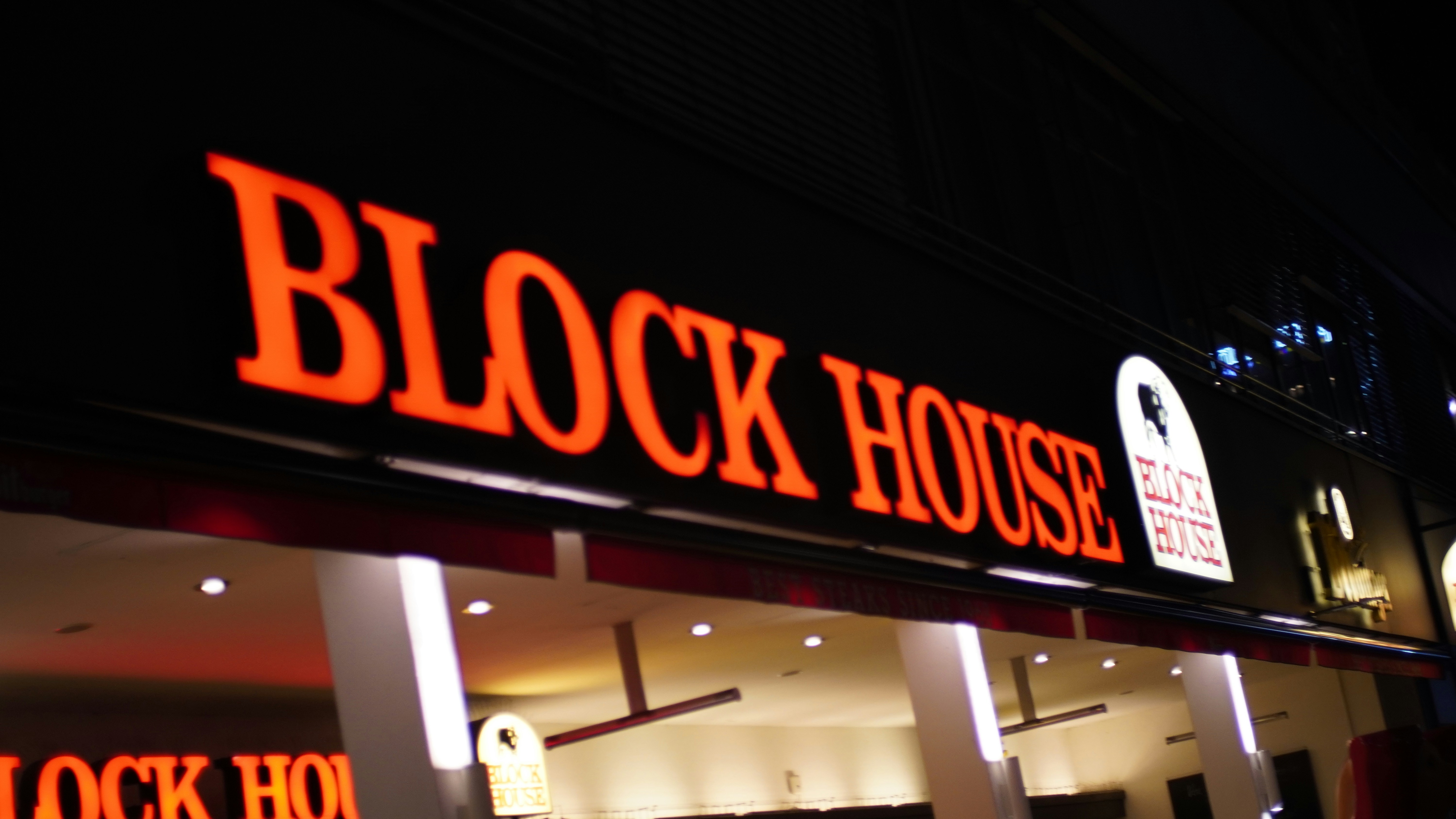 Block House Neon Sign: A Warm Beacon Across a Dim Street