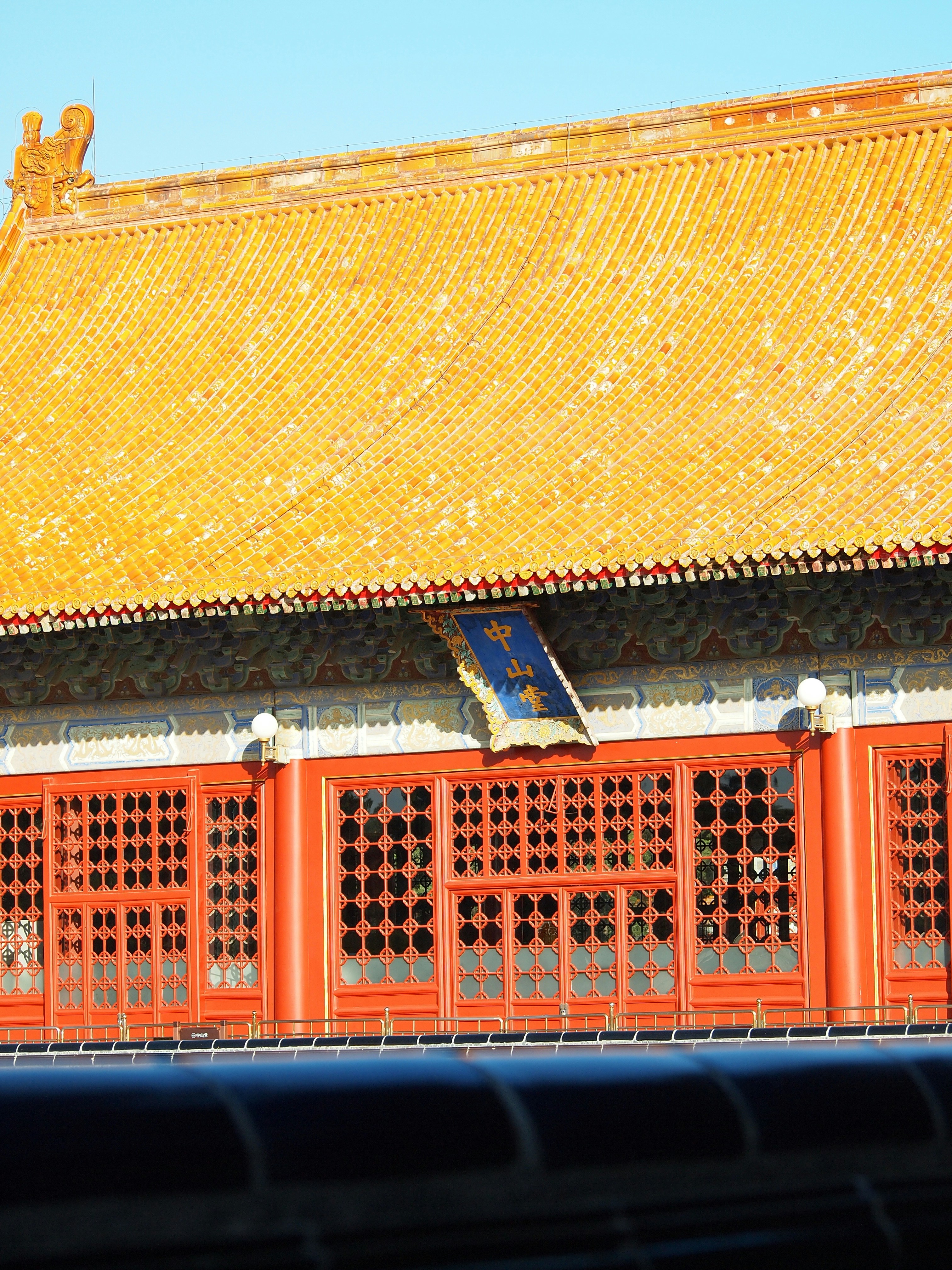 Crimson Lattice Amid Sunlit Tiles: A Temple Balcony Close-Up