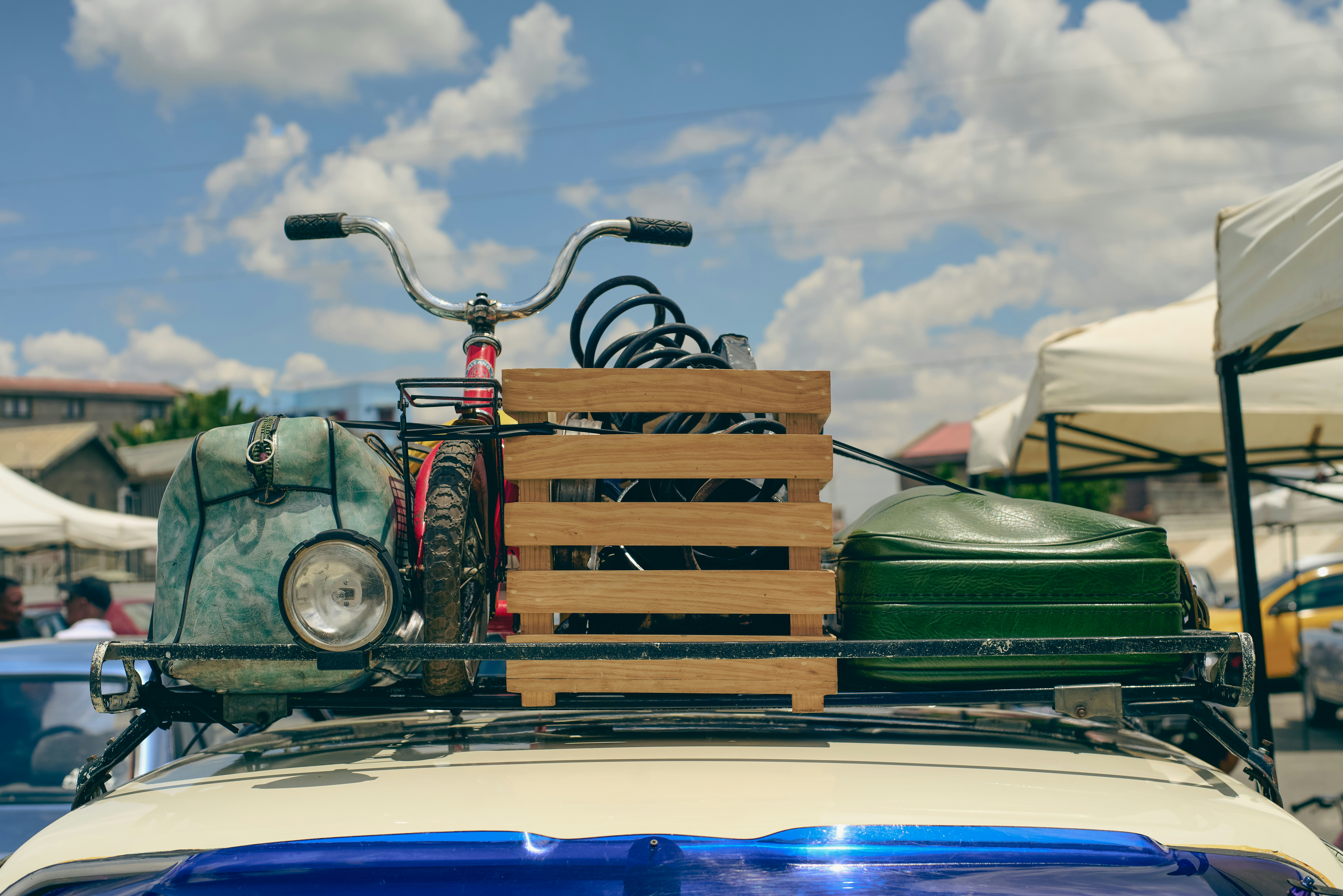 Rustic cargo on a car roof: vintage bike and crate under a bright sky