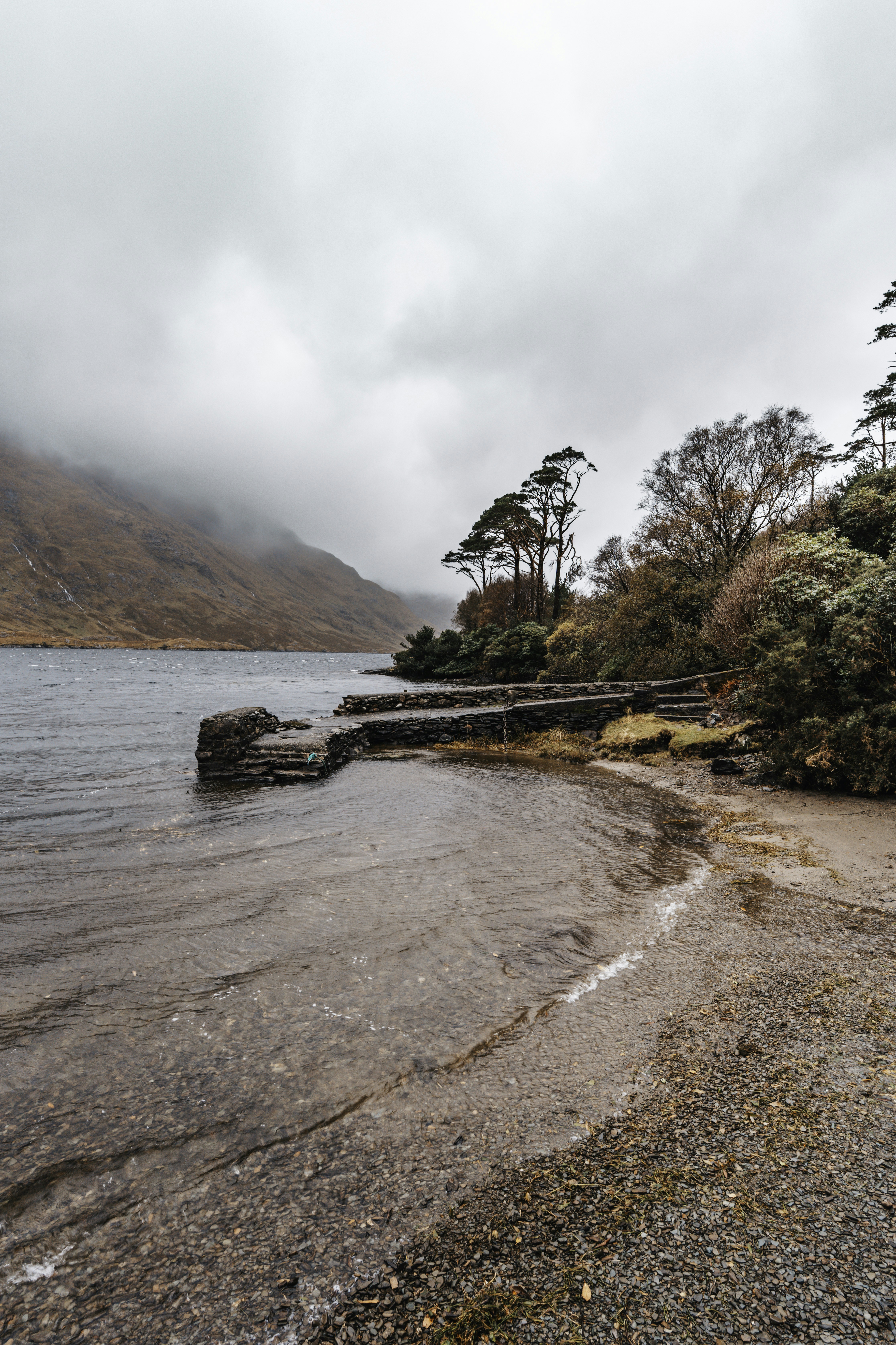 Mist-Lapped Jetty: Stone Path into a Quiet Lake Under Clouded Peaks