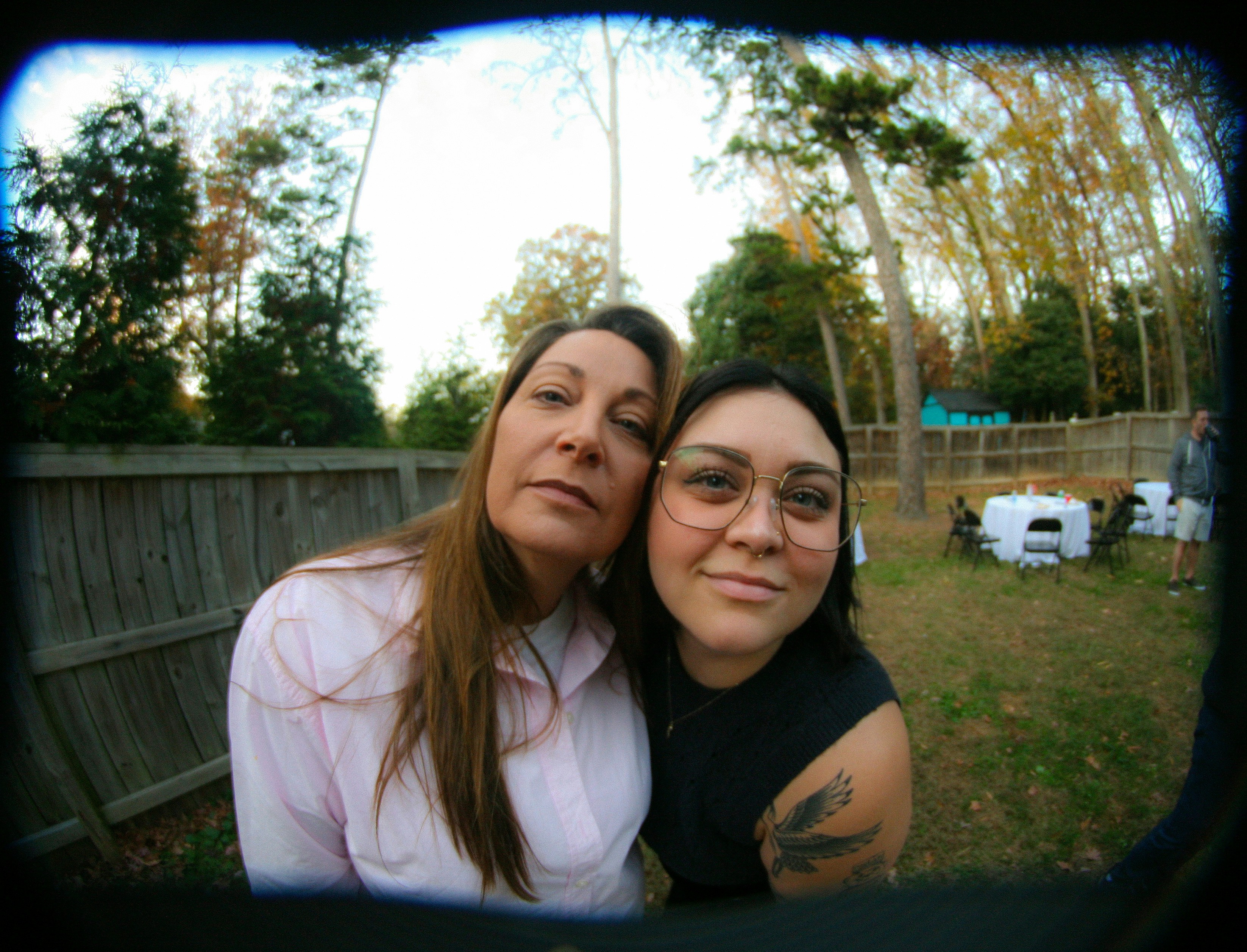 Two friends leaning in for a sunlit backyard selfie