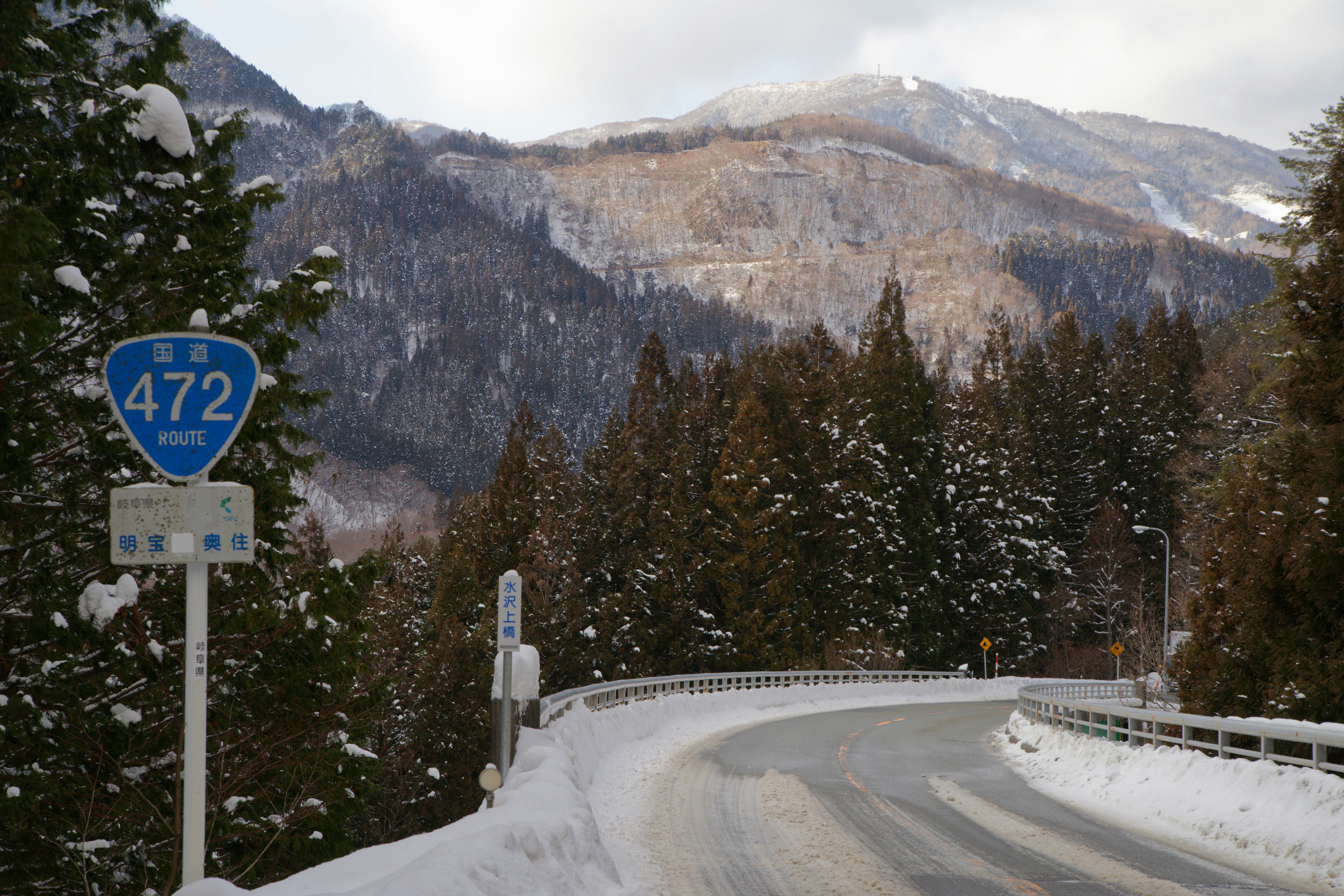 Snowy road with route 472 sign and mountains