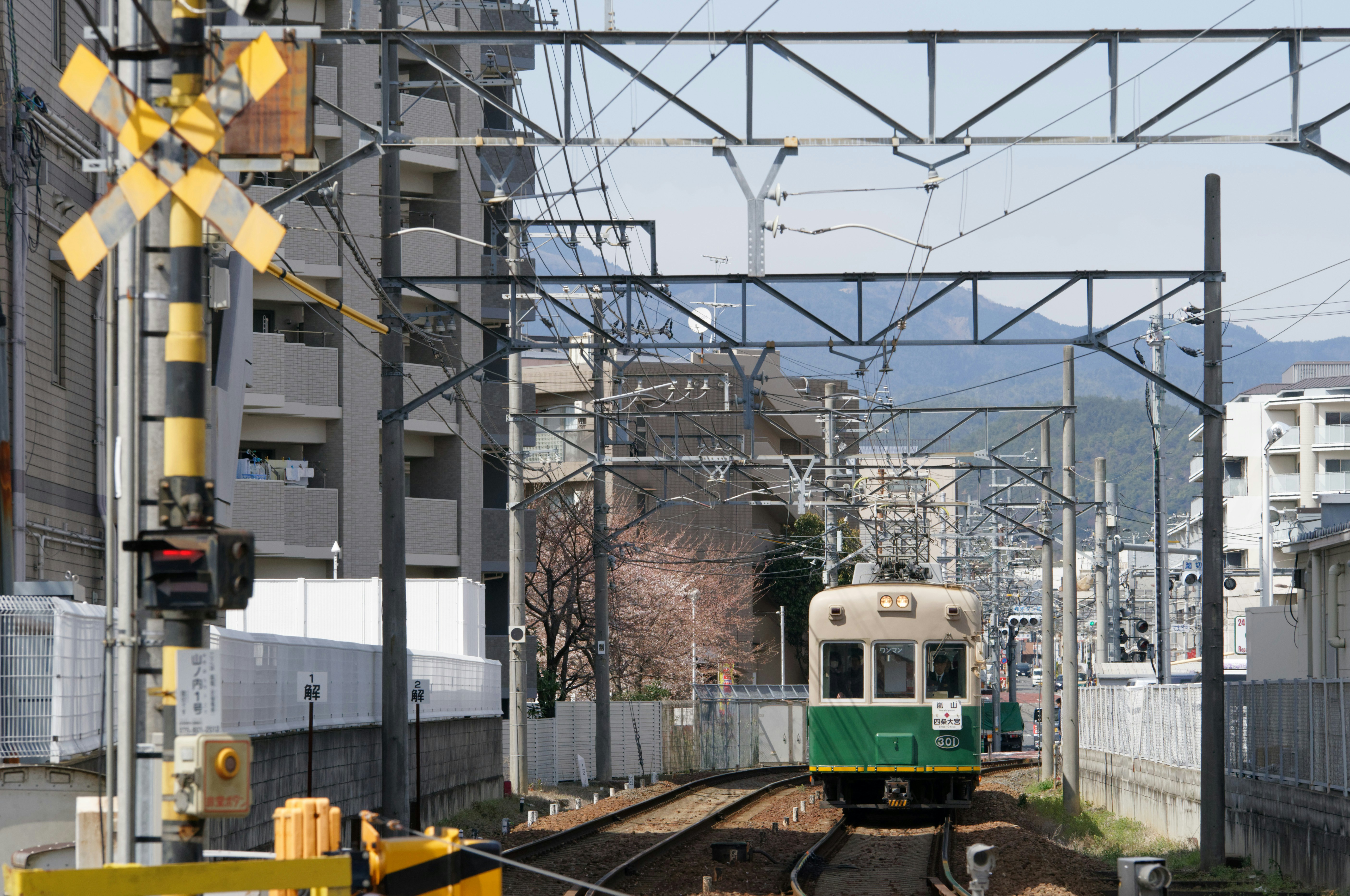 A train approaches a railroad crossing with buildings.