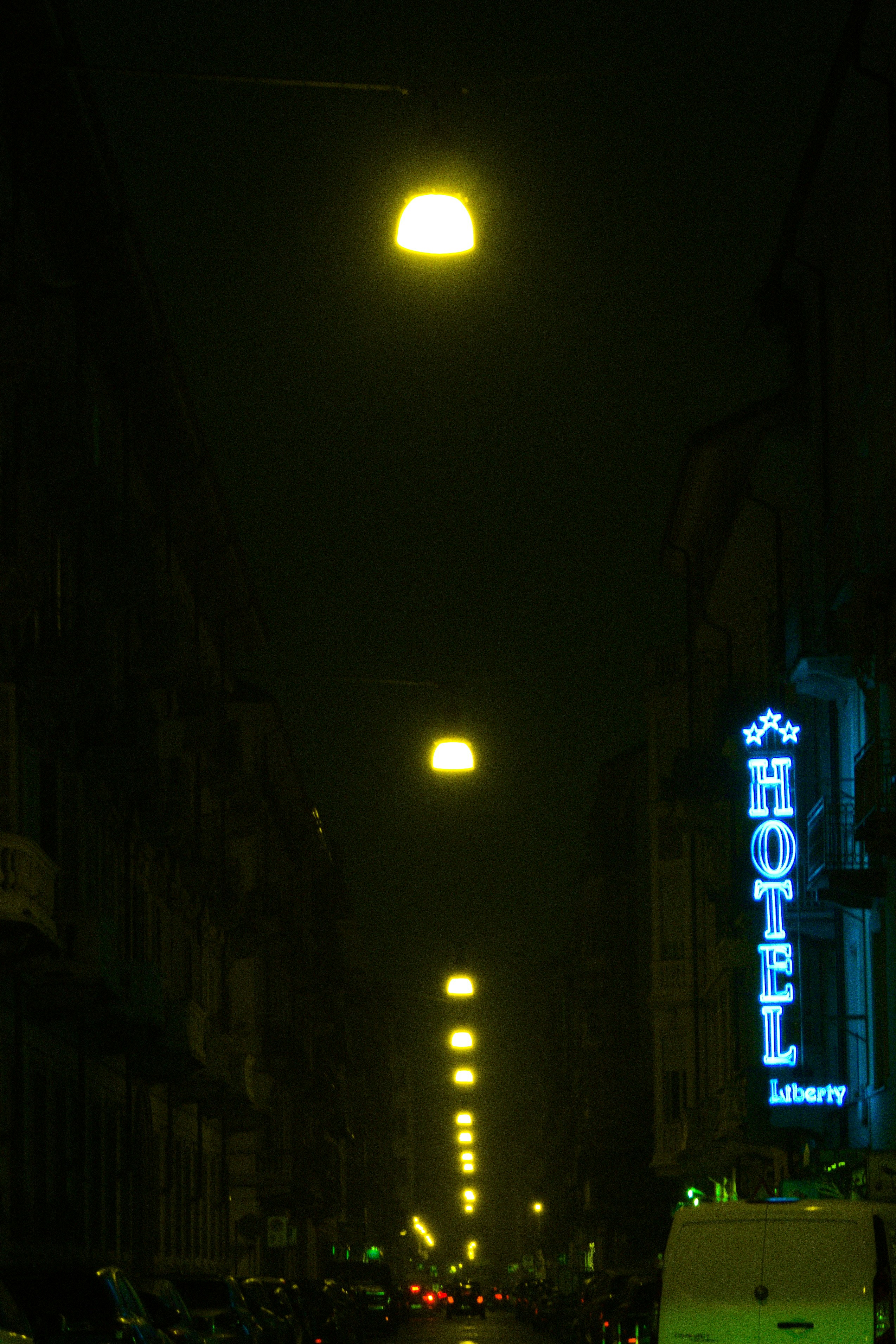 Amber Streetlights Converge Toward a Neon Hotel Sign