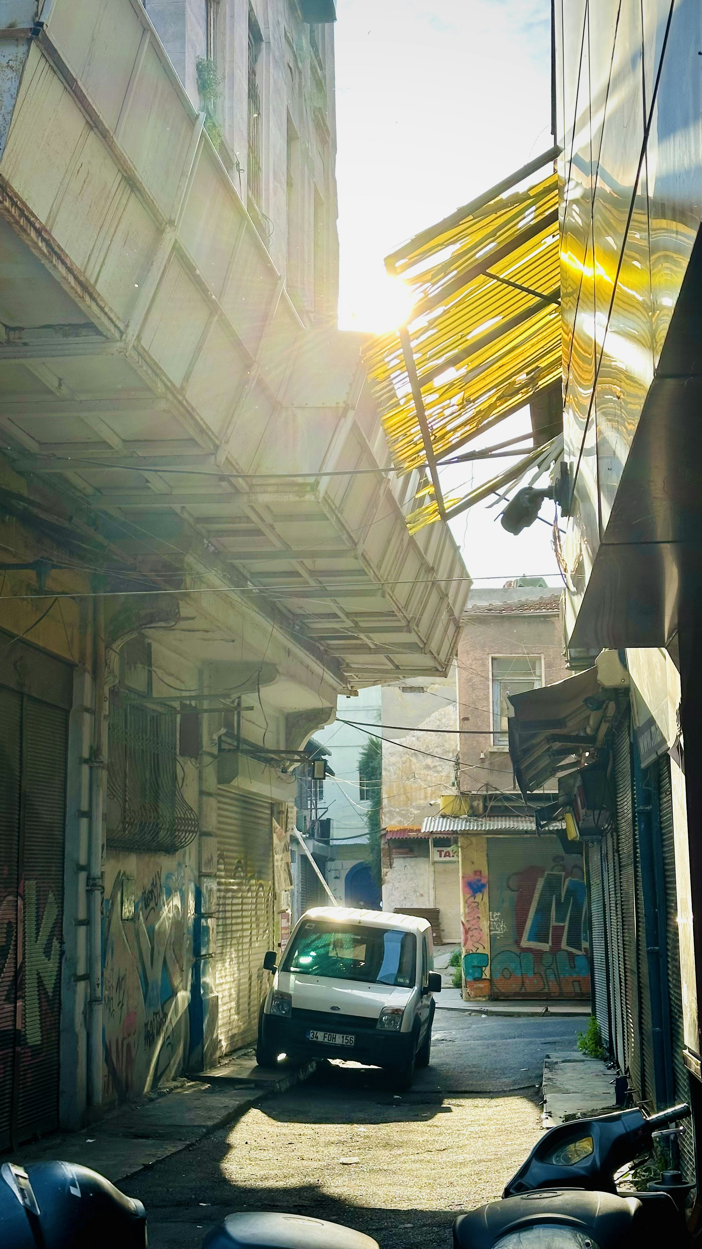 Sunlit Narrow: Graffiti Alley Converges on a Quiet Van
