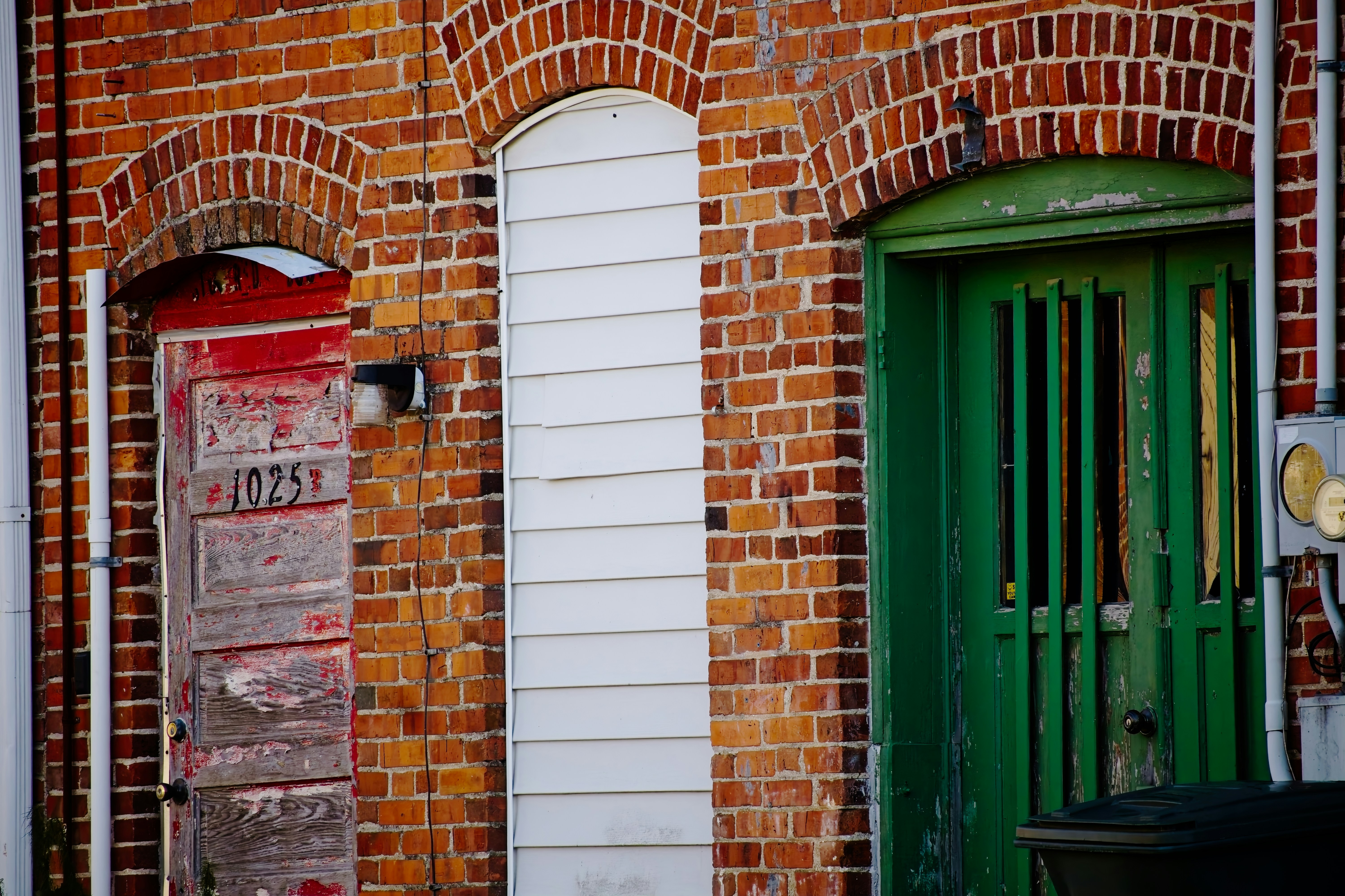 Three Doors, Three Textures: A Brick-Faced Composition of Red, White, and Green
