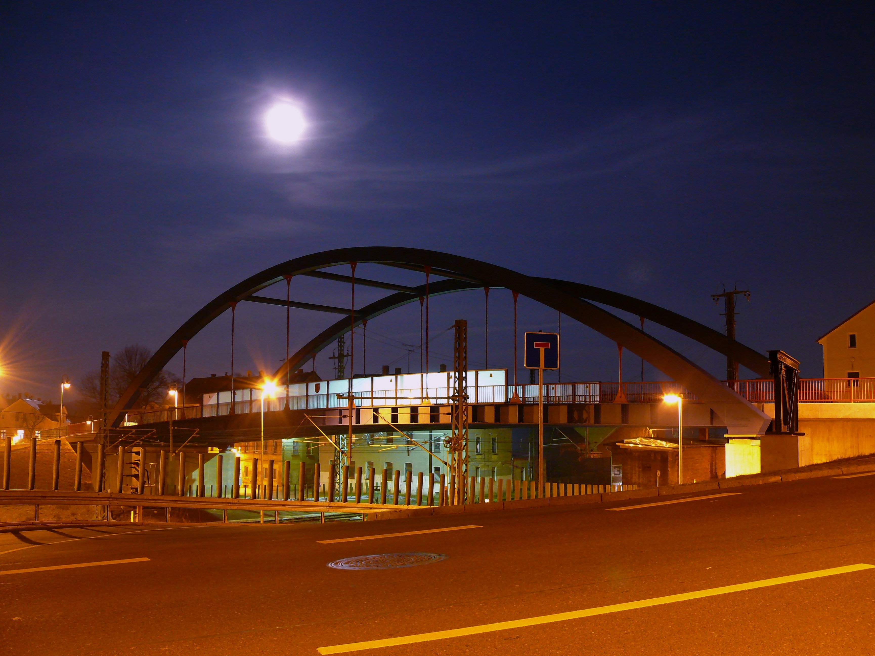 Moonlit Arc Over Quiet Street: Night Bridge Framed by Warm Glow