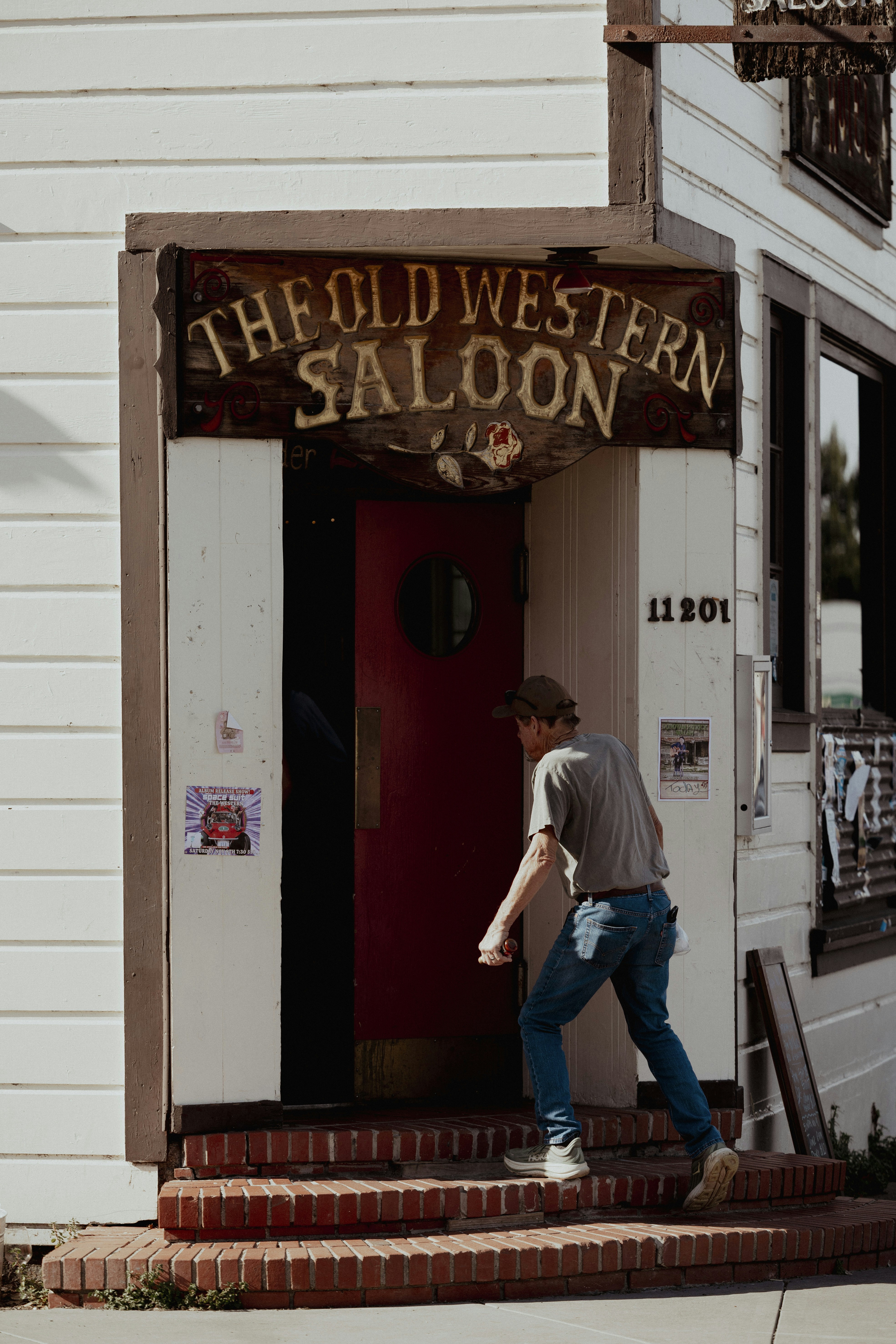 Brick-Threshold Moment at The Old Western Saloon: A lone visitor steps into a weathered doorway