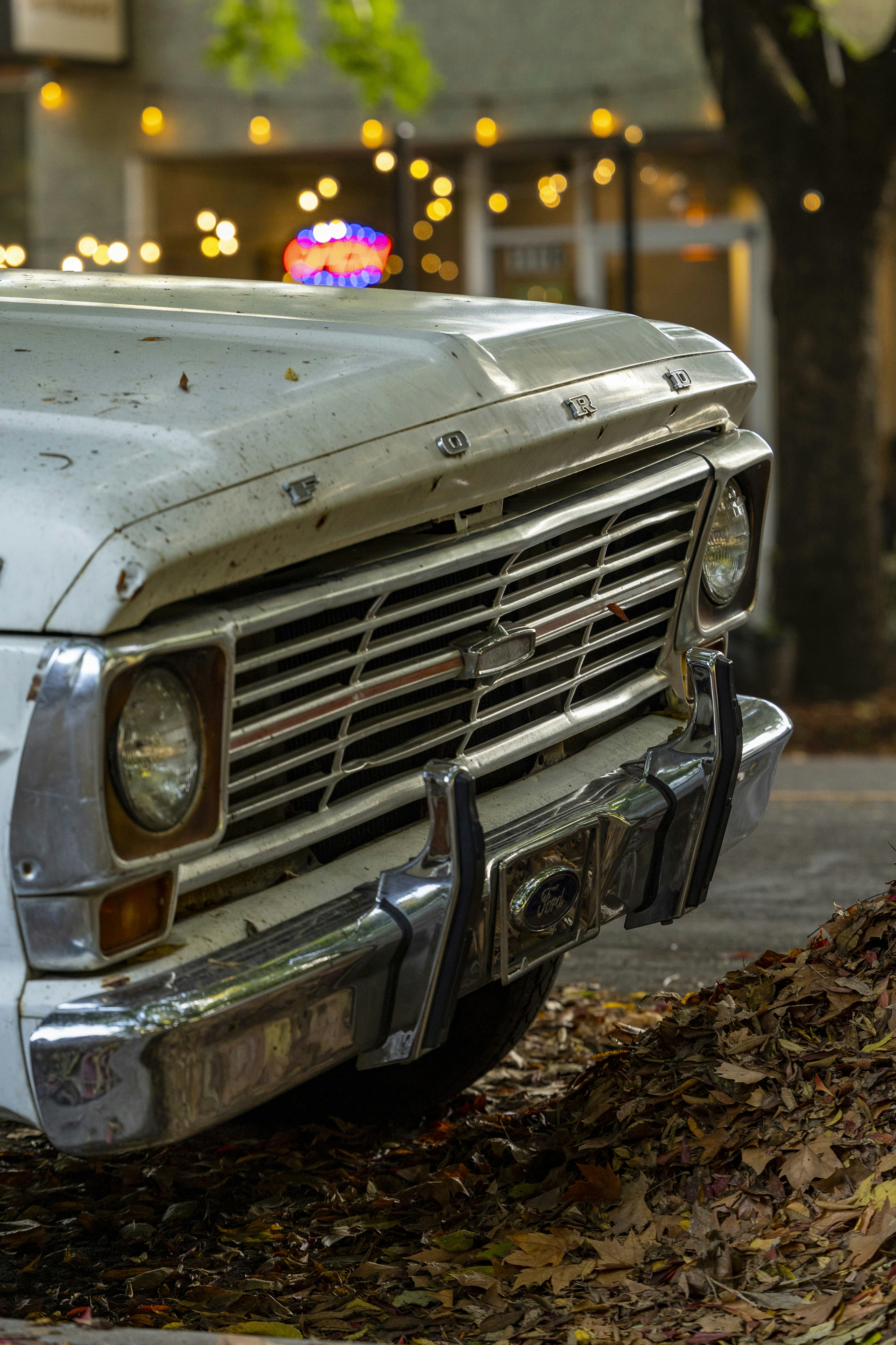 Chrome Relic Under Fall Lights: A Weathered Chevy Front End