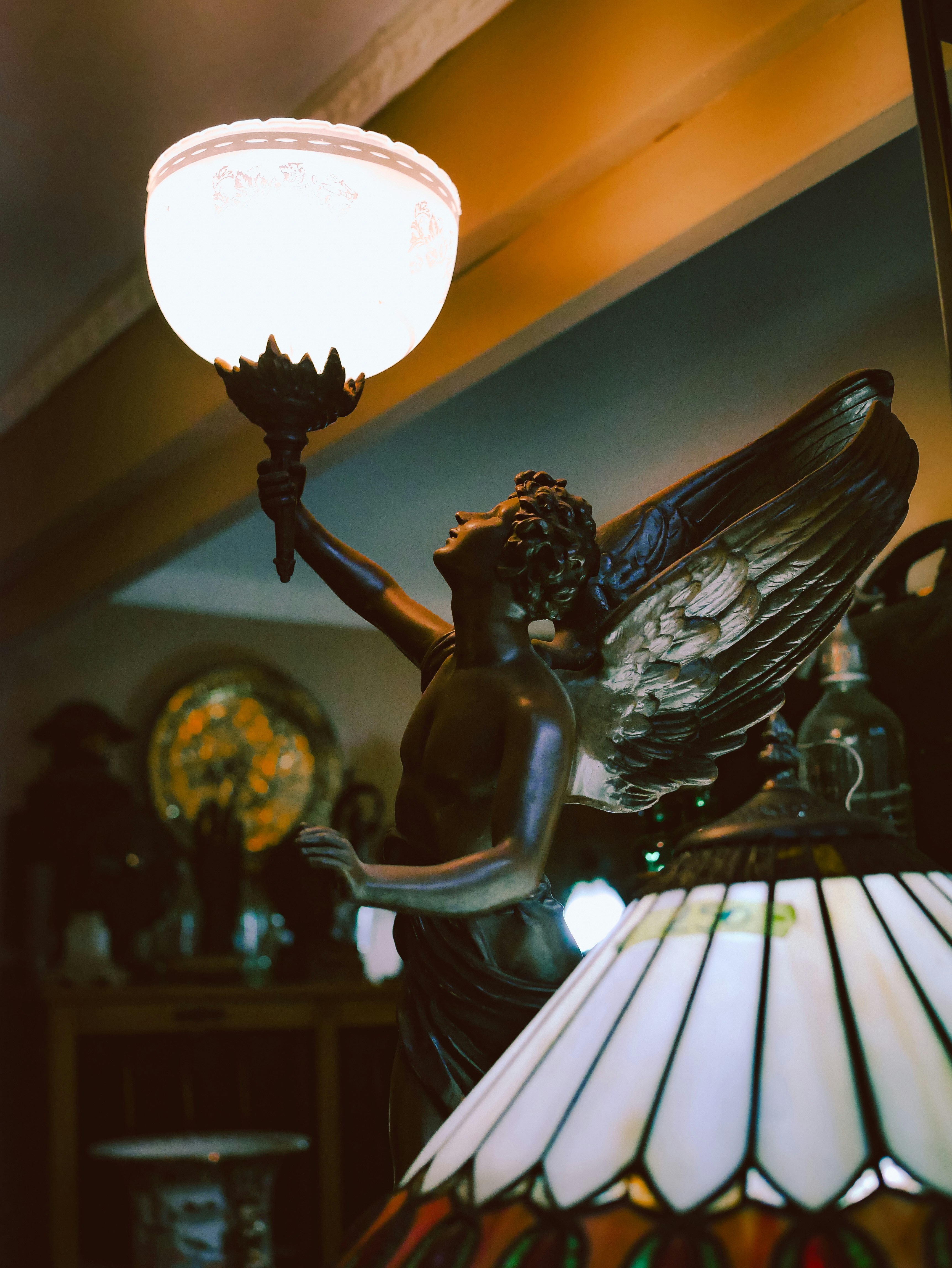 Angelic Reach Toward a Glass Globe in a Warm Vintage Lamp Shop
