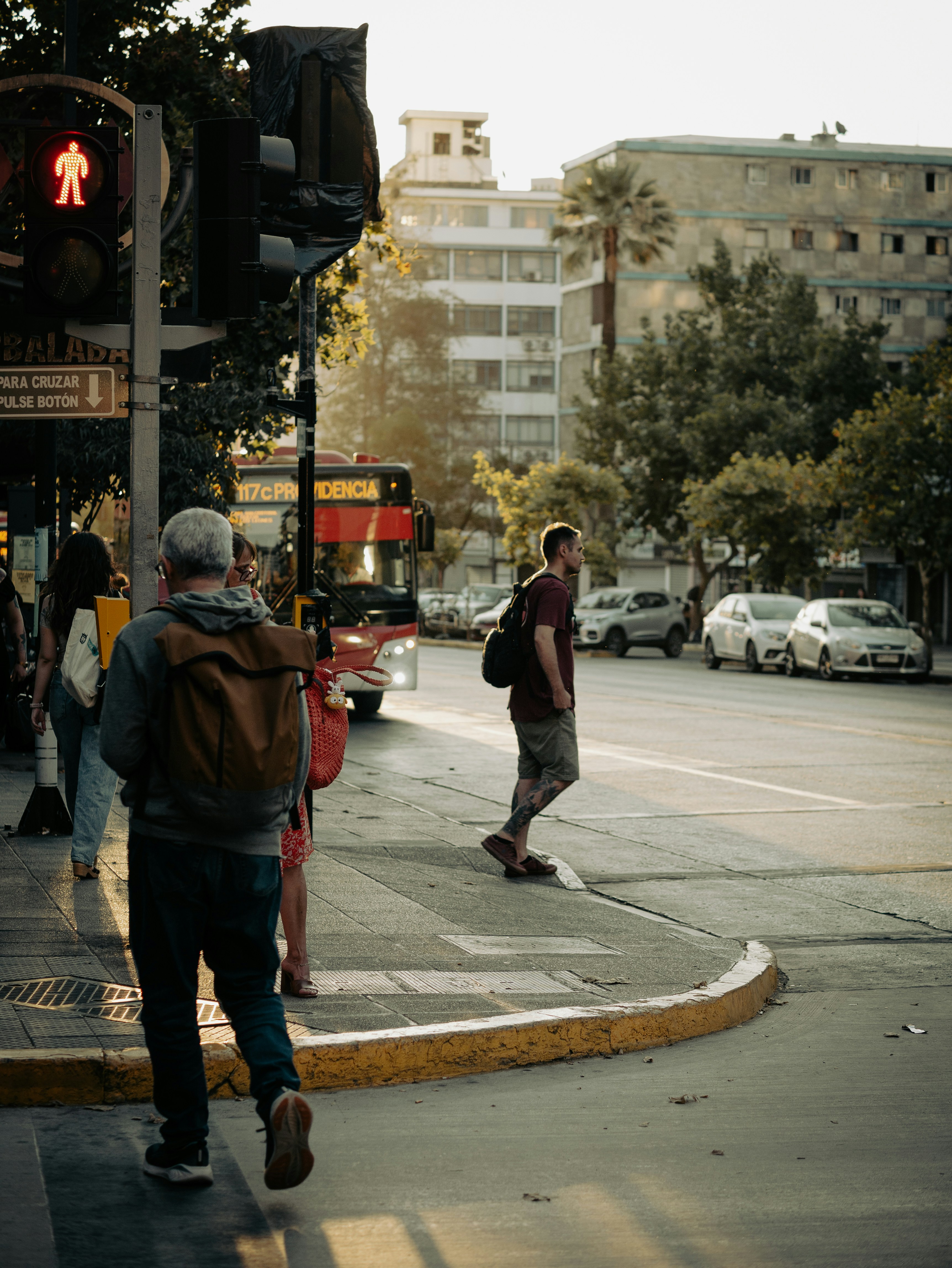 Crosswalk Convergence: A Man in Maroon Crossing Amid City Traffic