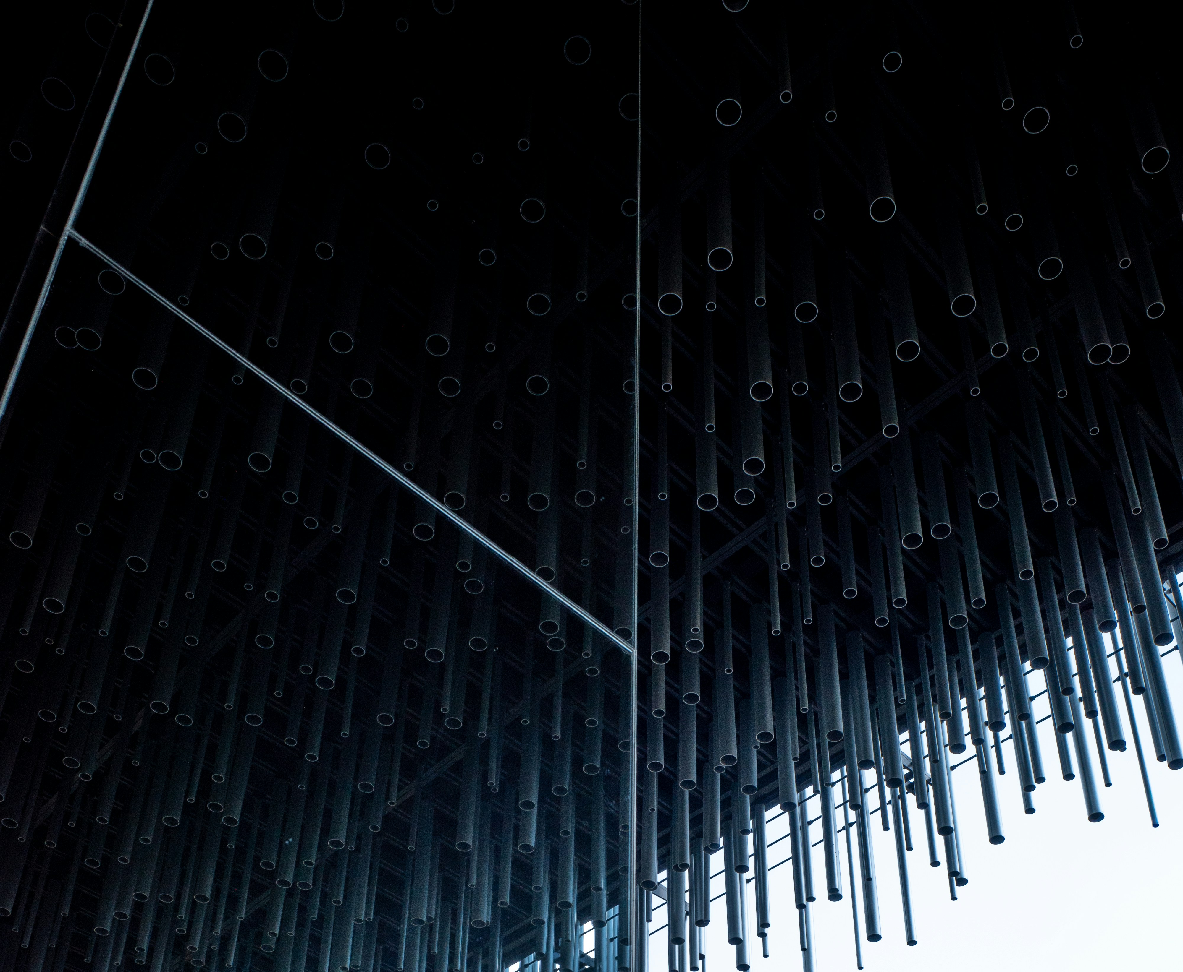 Dark ceiling with many hanging cylindrical objects.