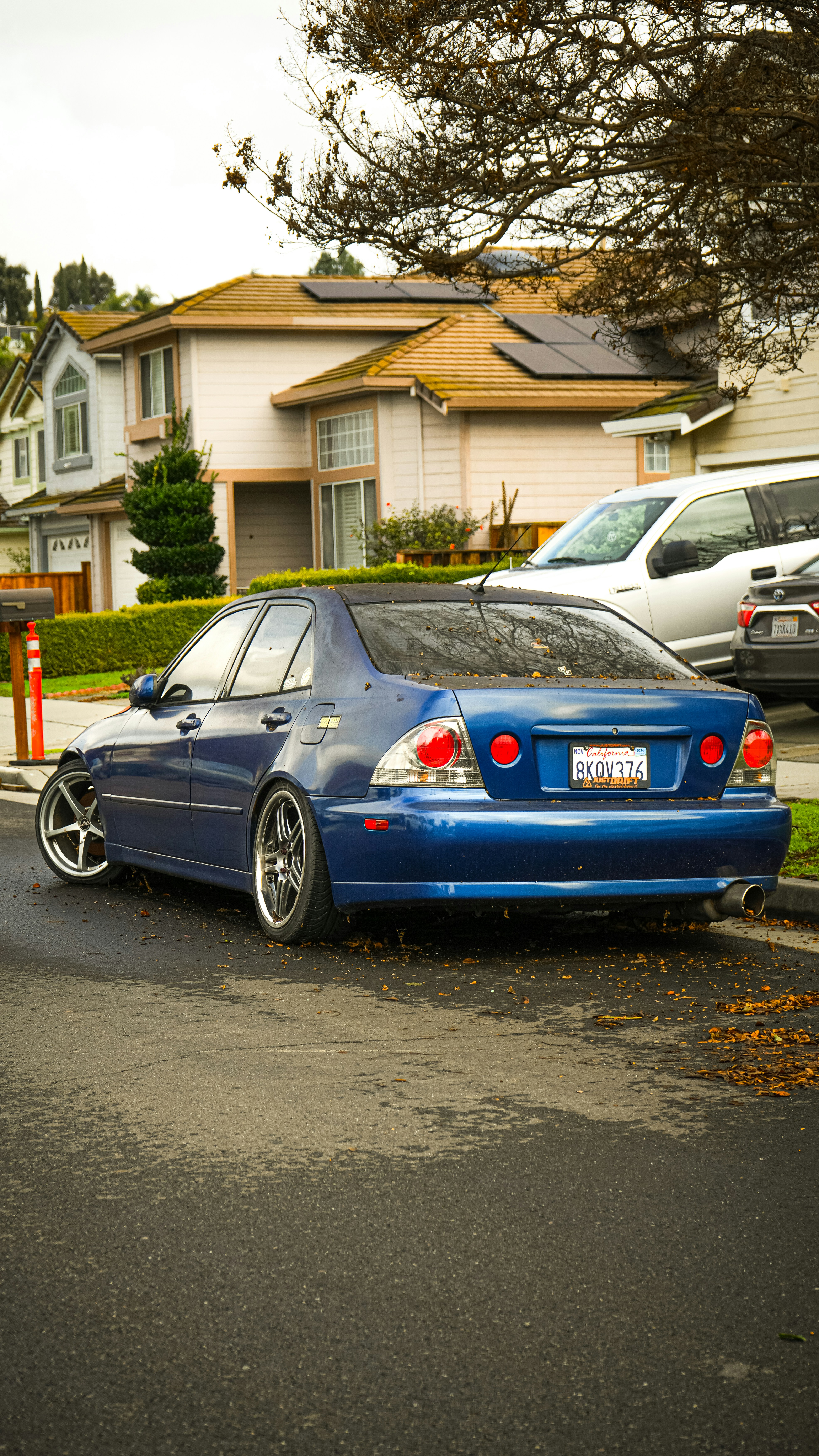 Low-Slung Blue Sedan Anchors a Quiet Suburban Street