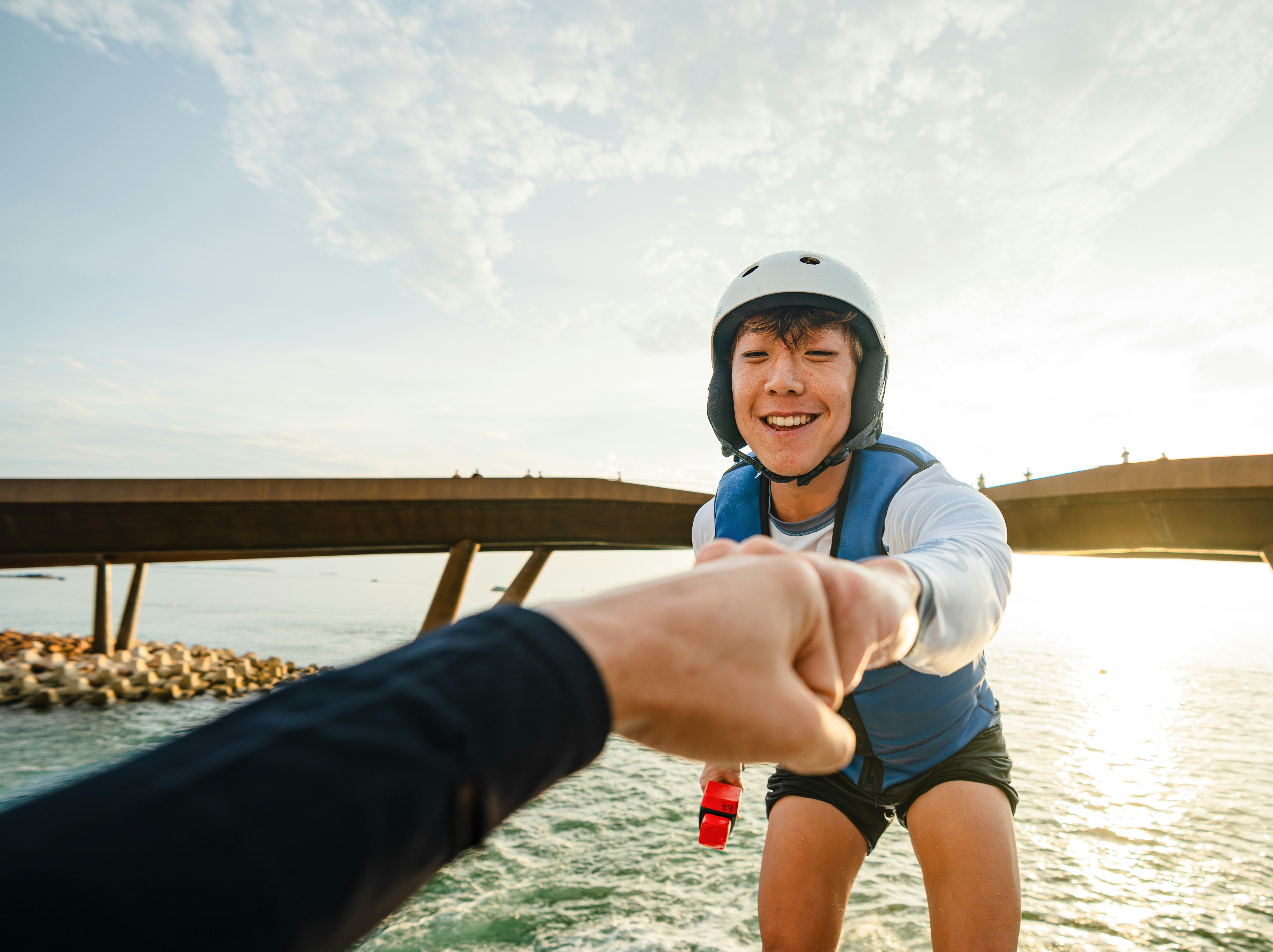 Sunlit Harbor Fist-Bump: Helmeted Rider Reaches Toward the Camera