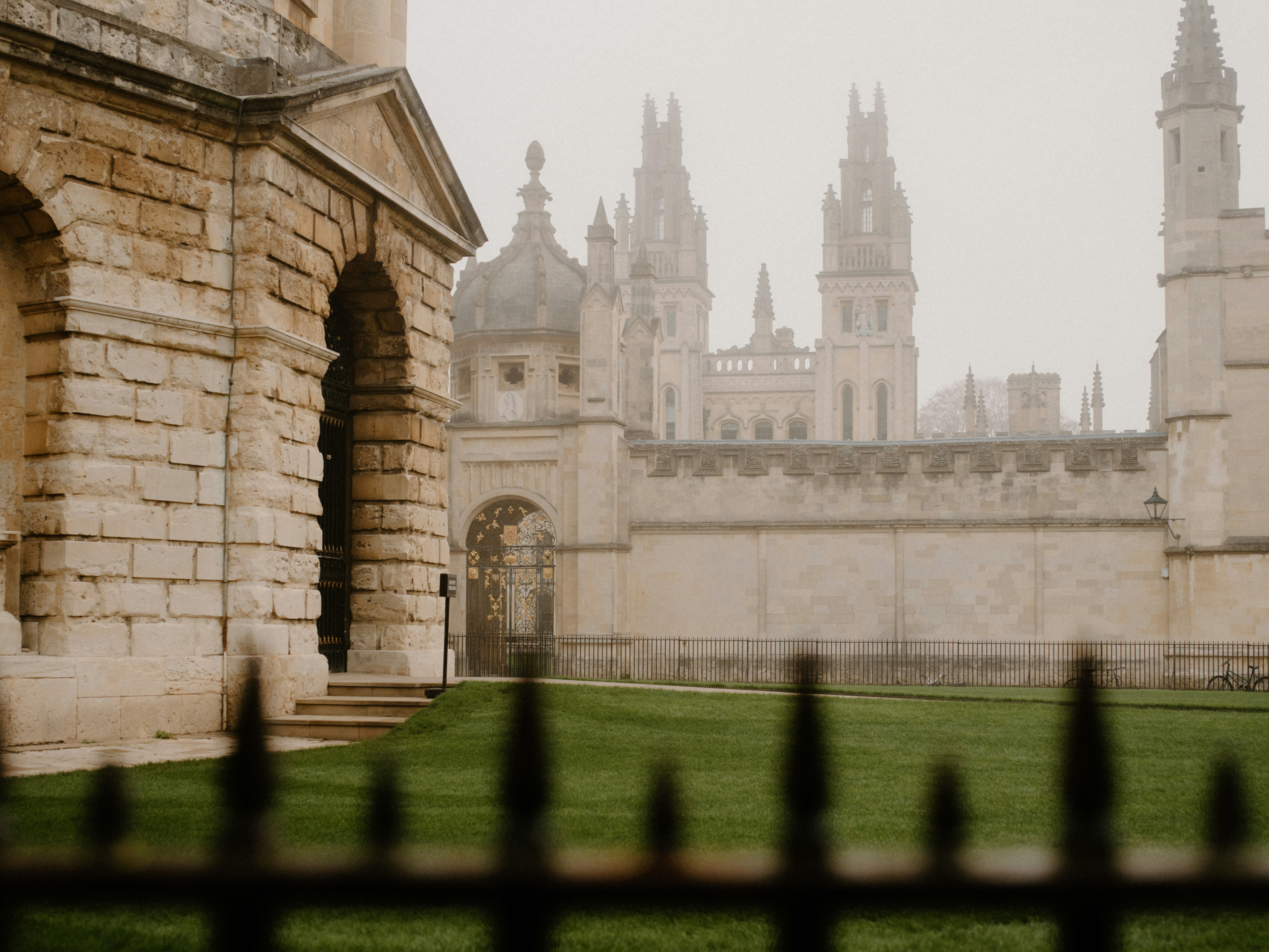 Misty view of historic university buildings with green lawn.