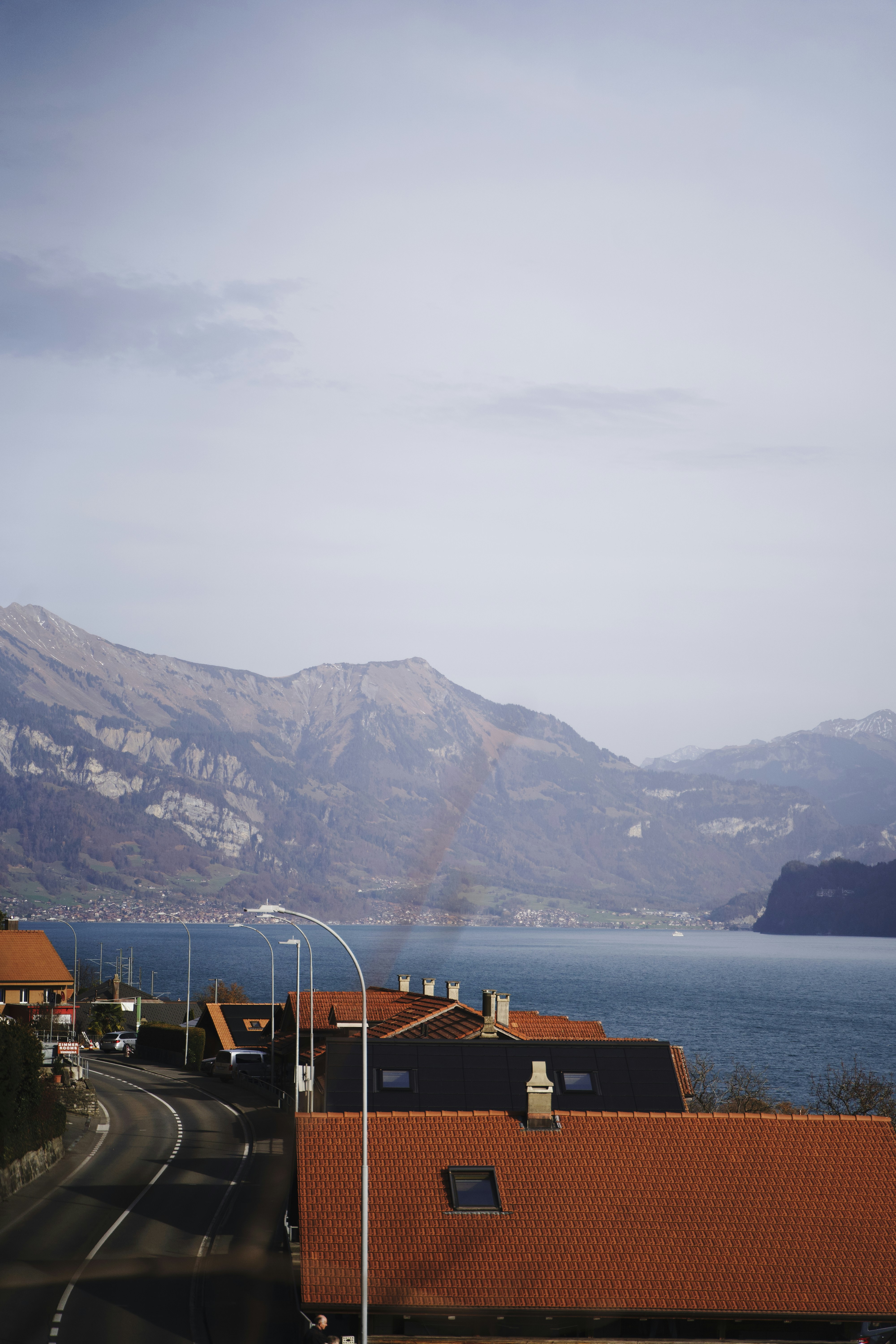 Red Roofs Along a Coastal Curve Beneath Alpine Giants