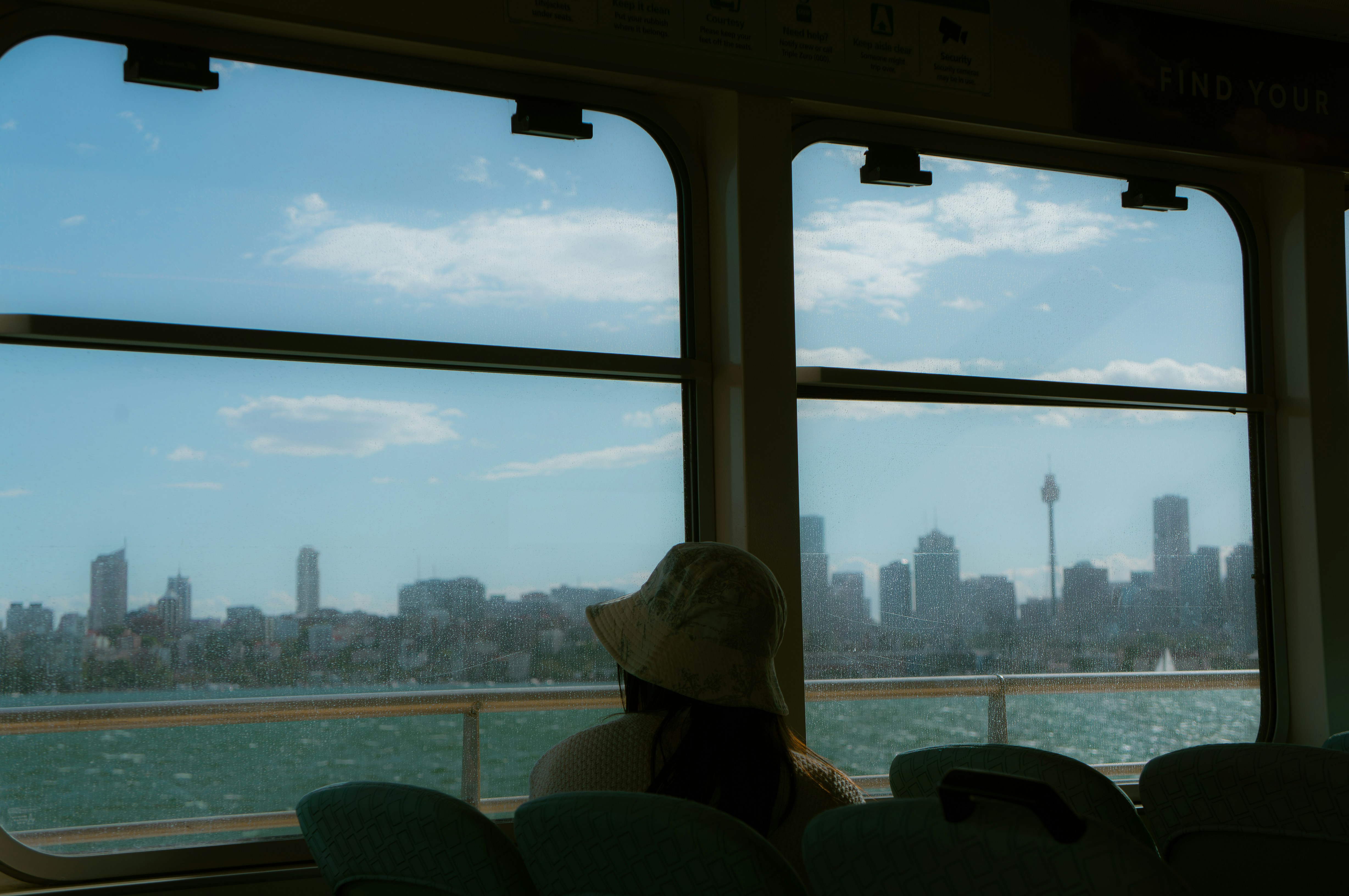 Harbor Window Reverie: Passenger Silhouette Against a Distant Skyline