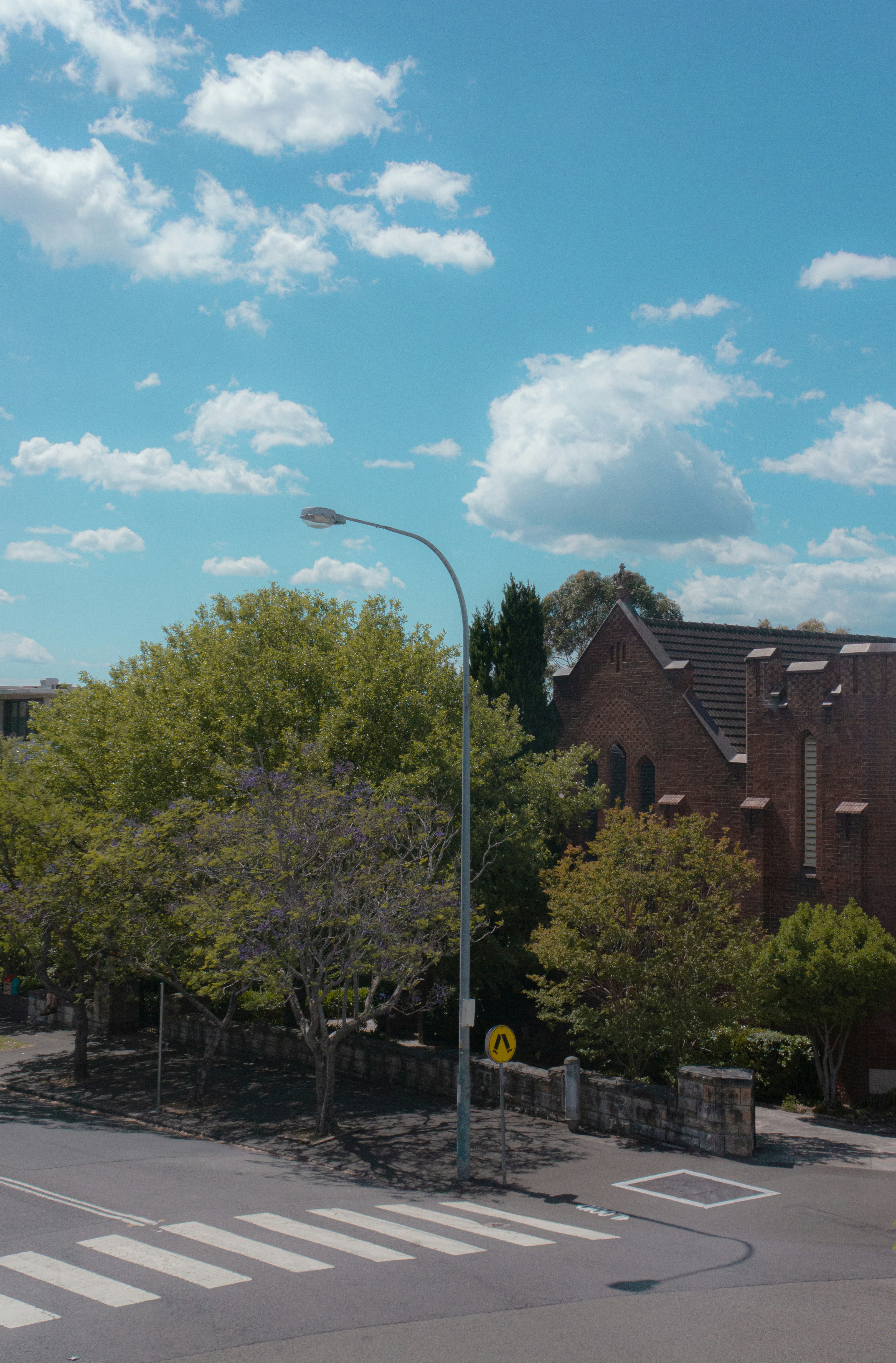 Curved Streetlamp Framing a Brick Campus Edge Beneath a Brisk Blue Sky