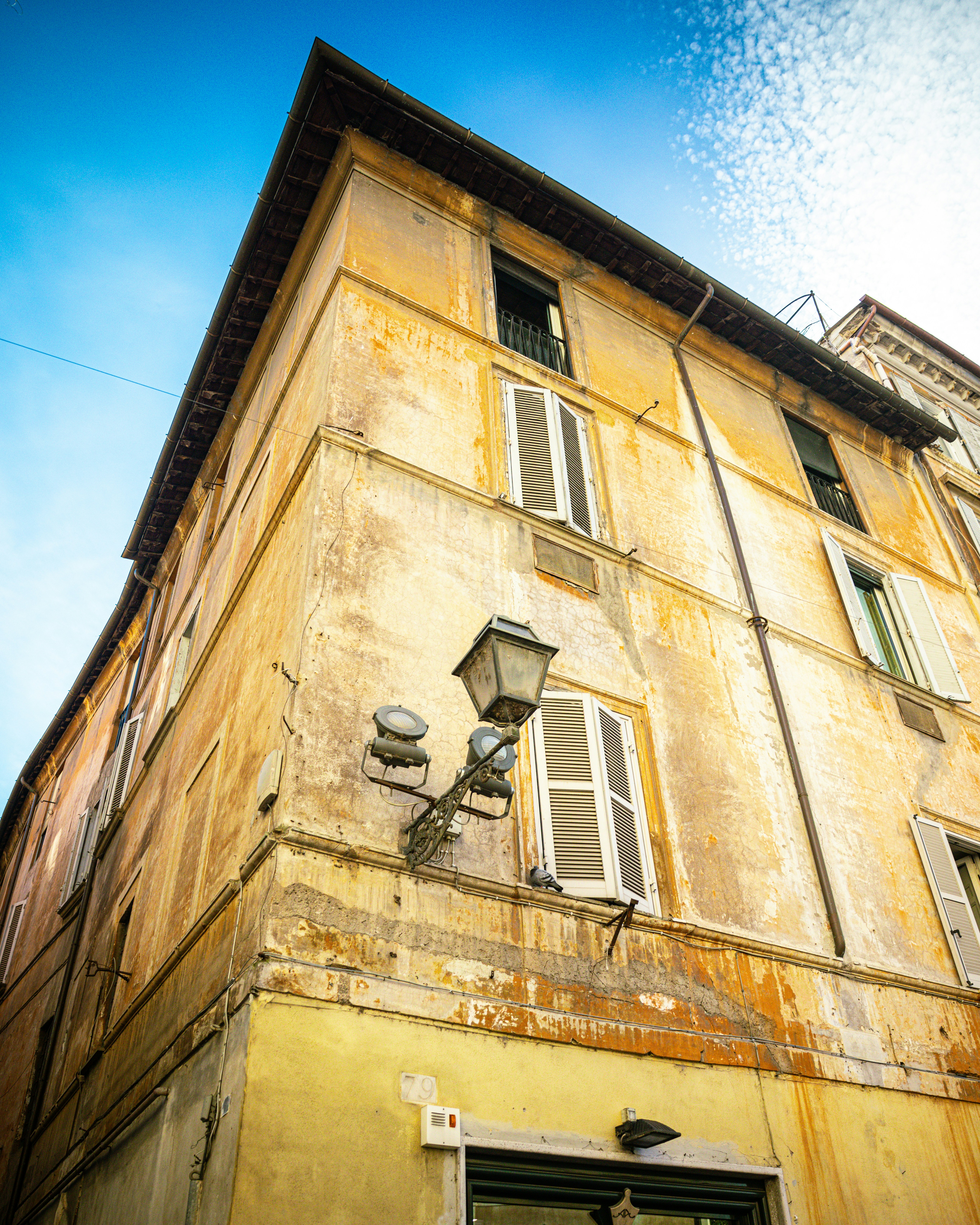 Sunlit Decay: Time-Worn Facade with a Watchful Lamp