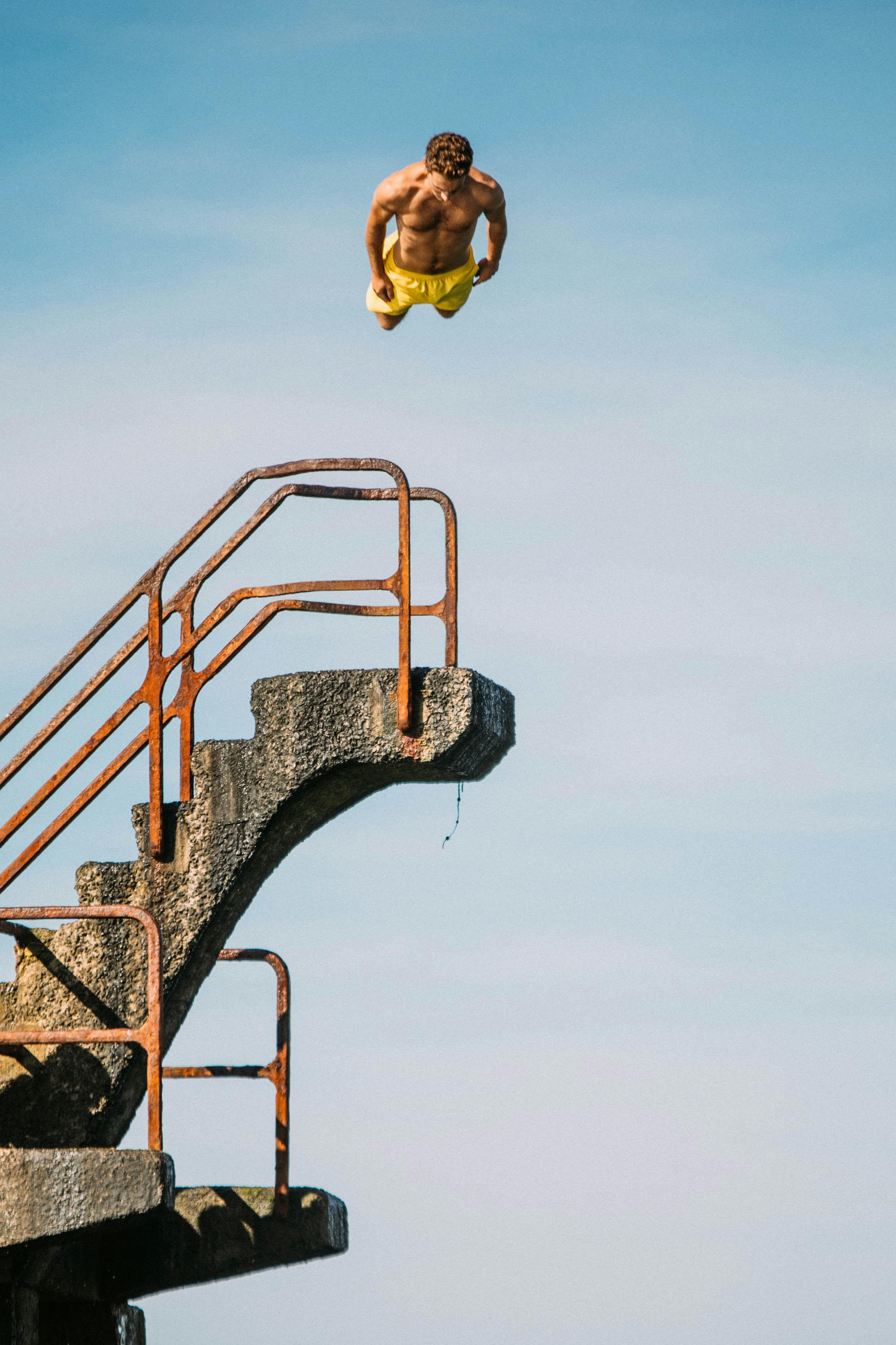 Leap Over Rust: The Diver's Quiet Break from a Weathered Platform