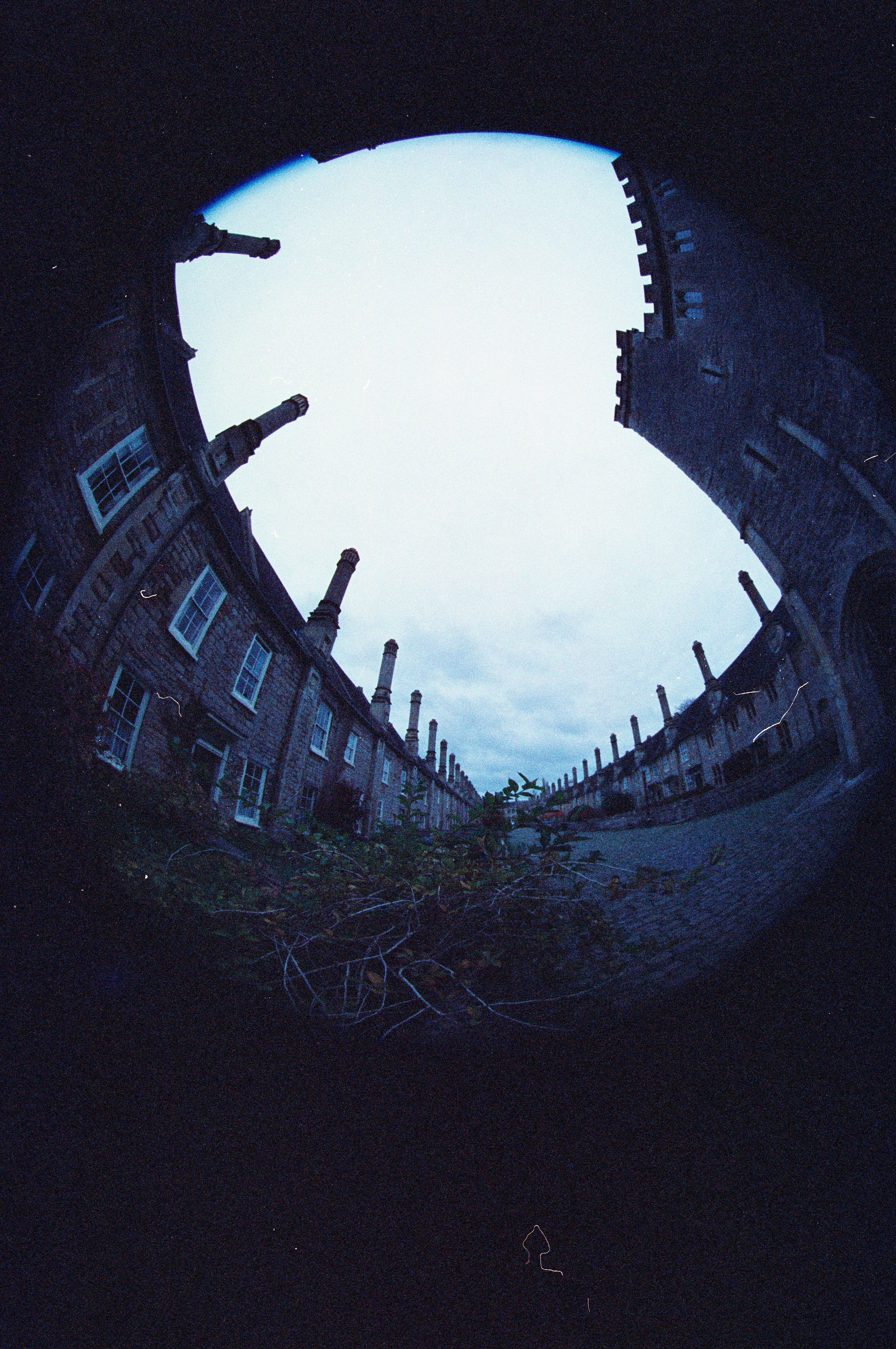 Fisheye view of old brick buildings under a cloudy sky