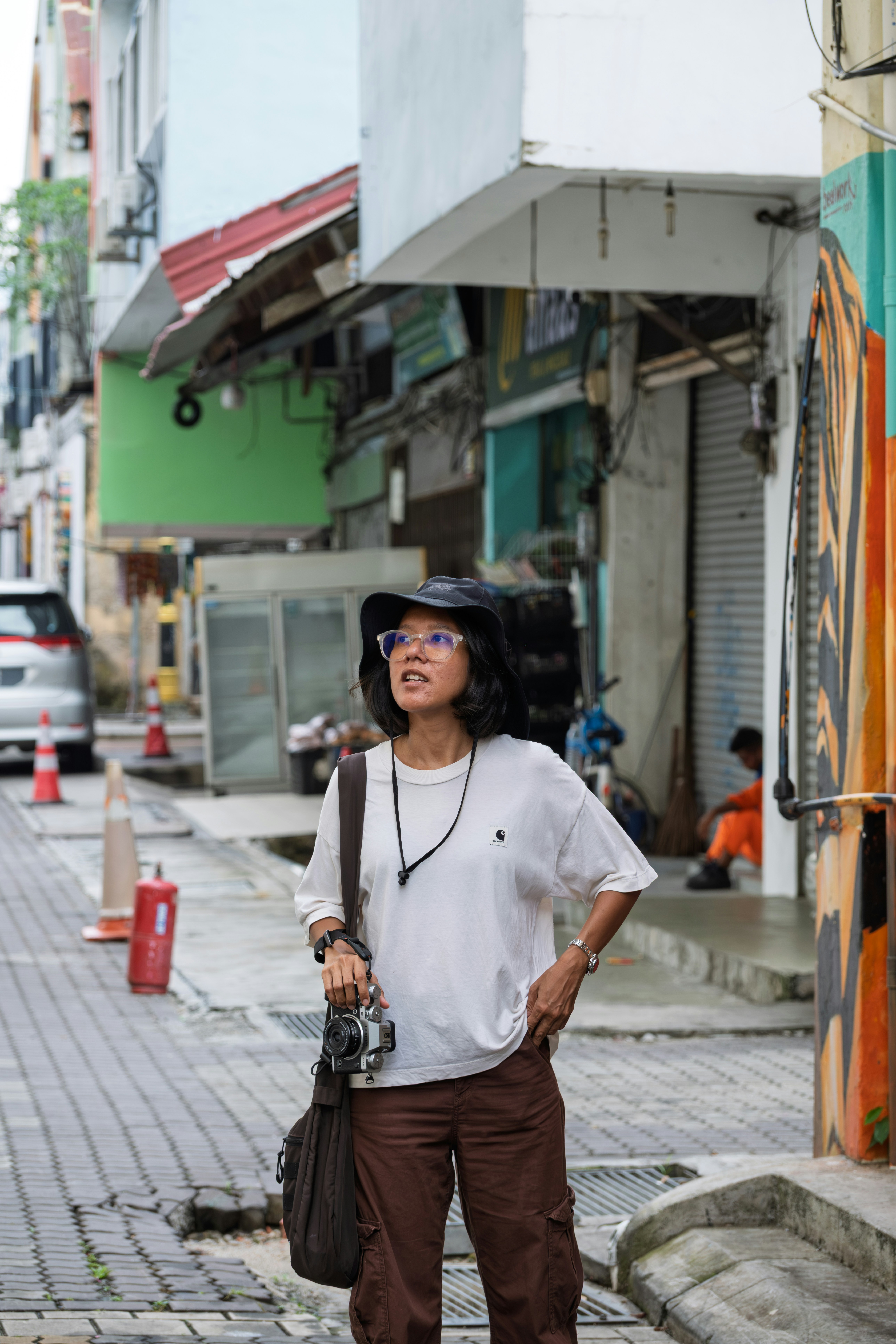 Crossing Focus: A Street Photographer Pauses with Camera in a Graffitied Alley