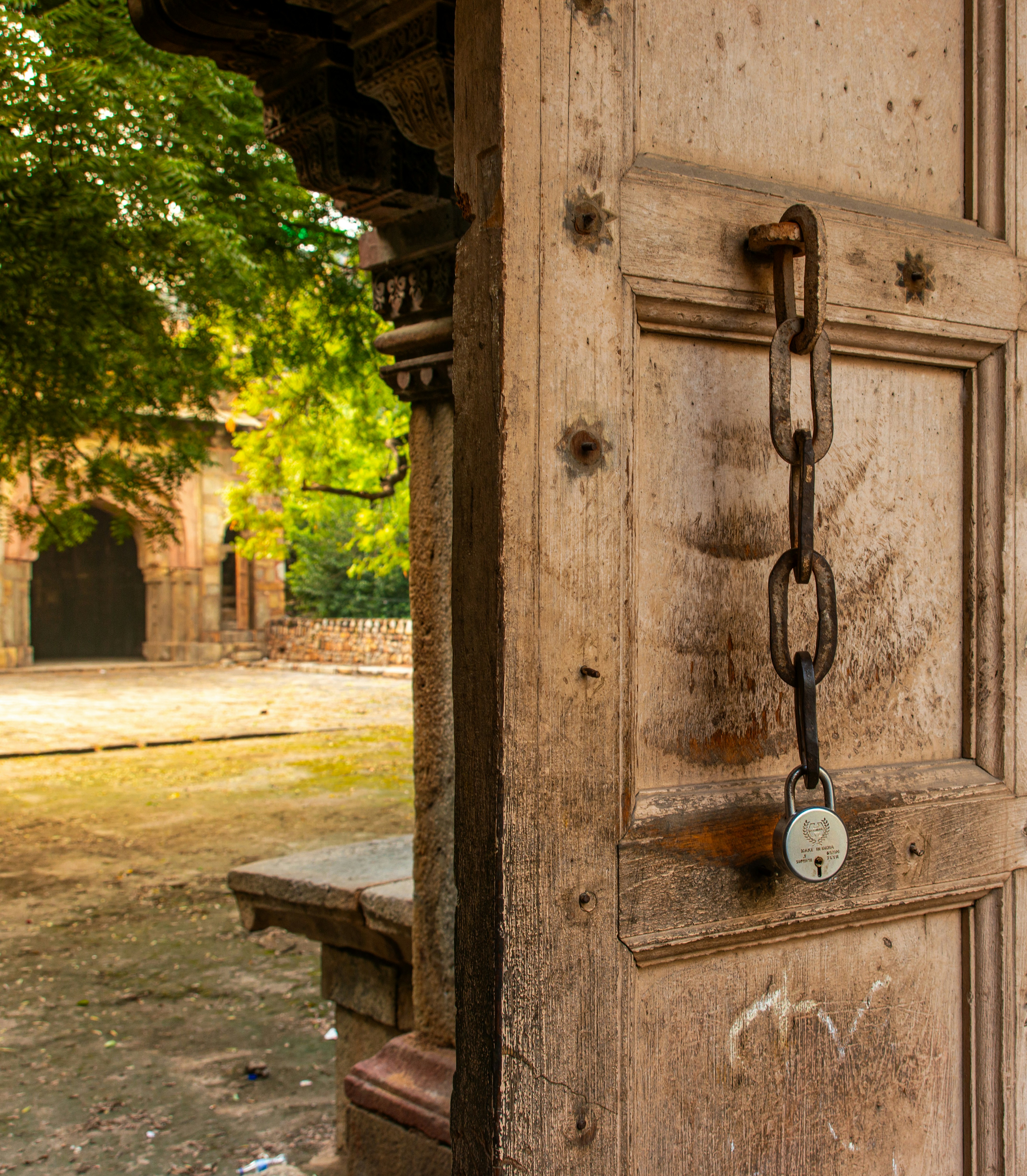 The white rustic wooden door entrance of Masjid Moth in Delhi, India.