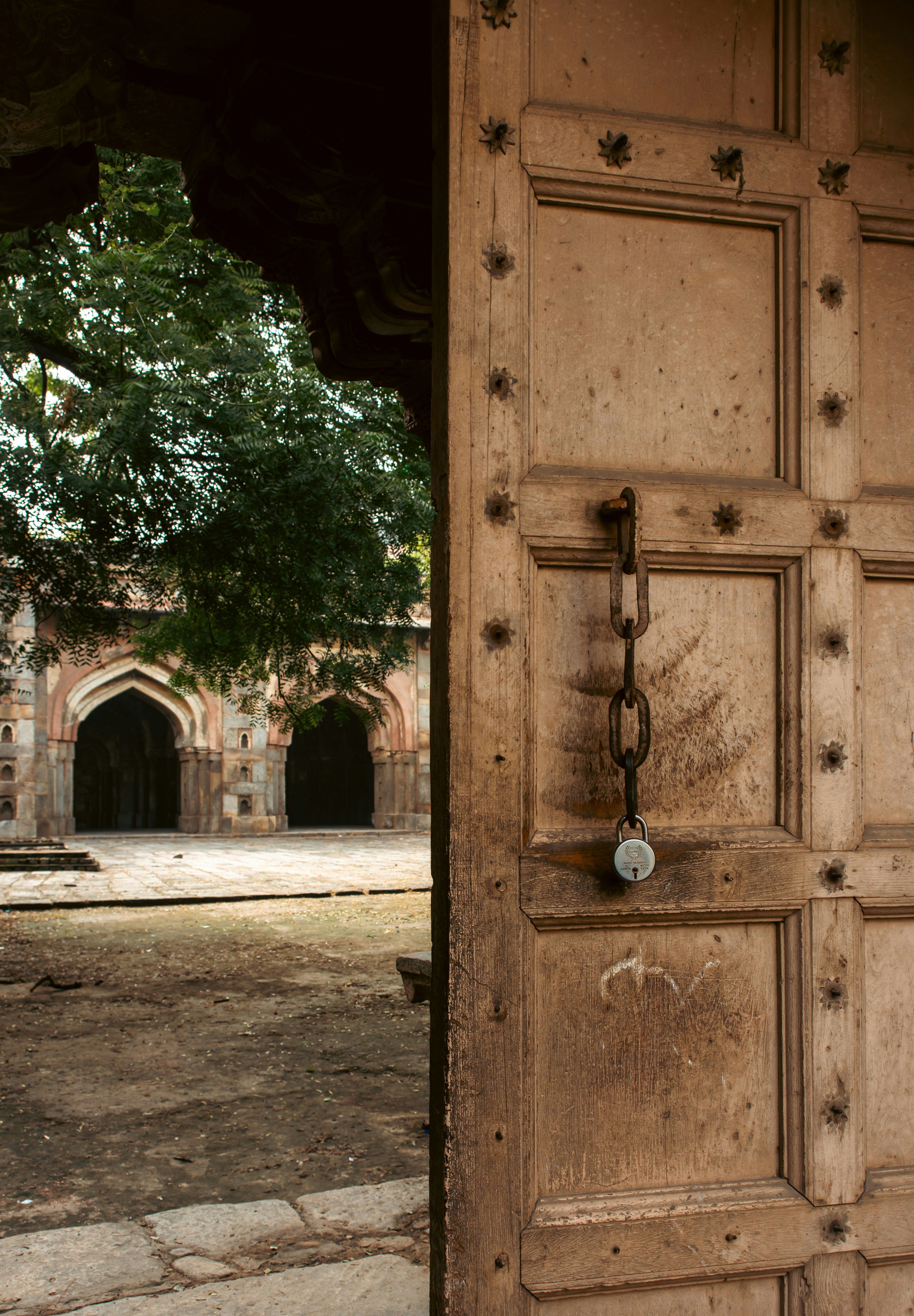 The white rustic wooden door entrance of Masjid Moth in Delhi, India.