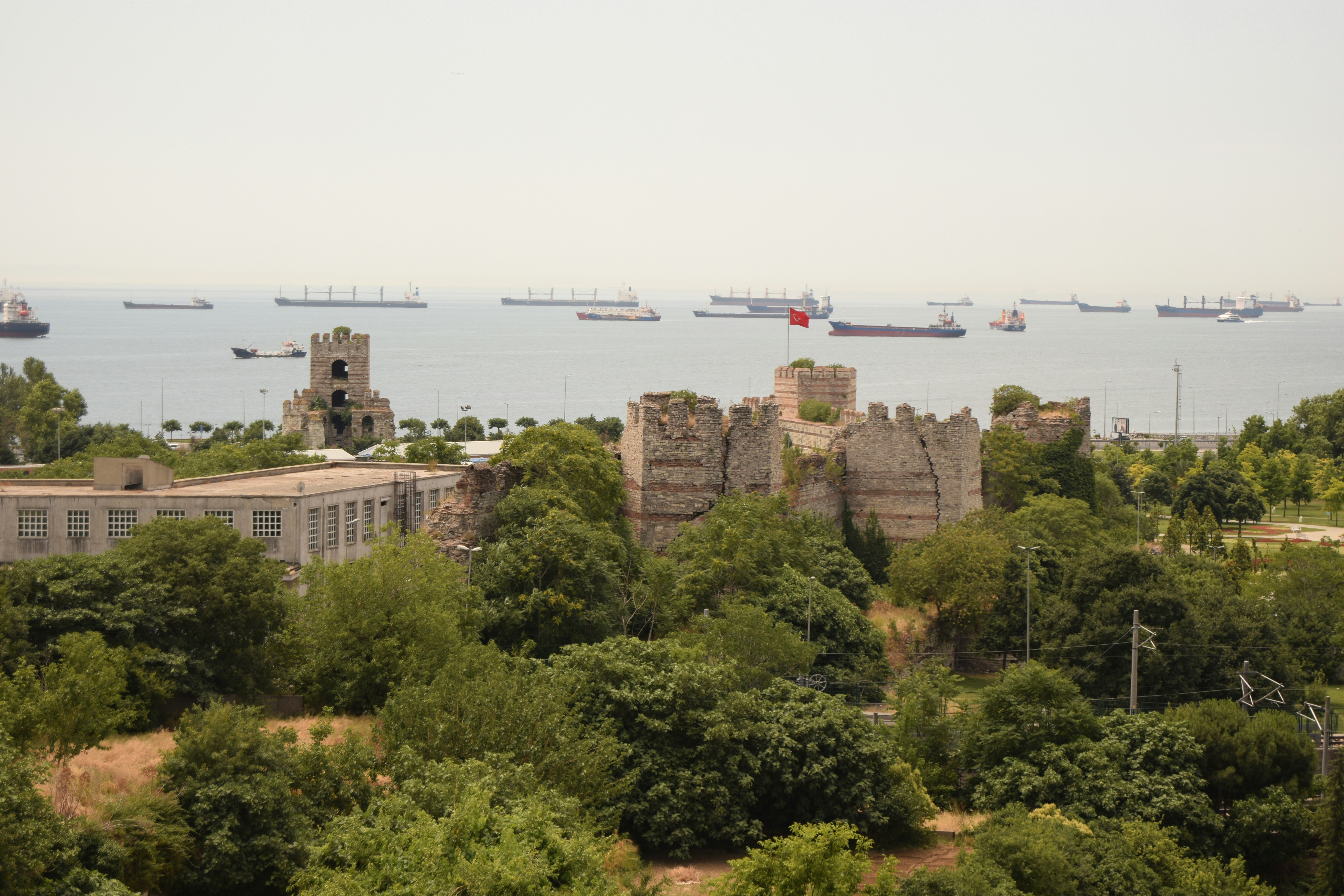 Flag atop the Ruined Fortress Framing a Fleet on the Horizon