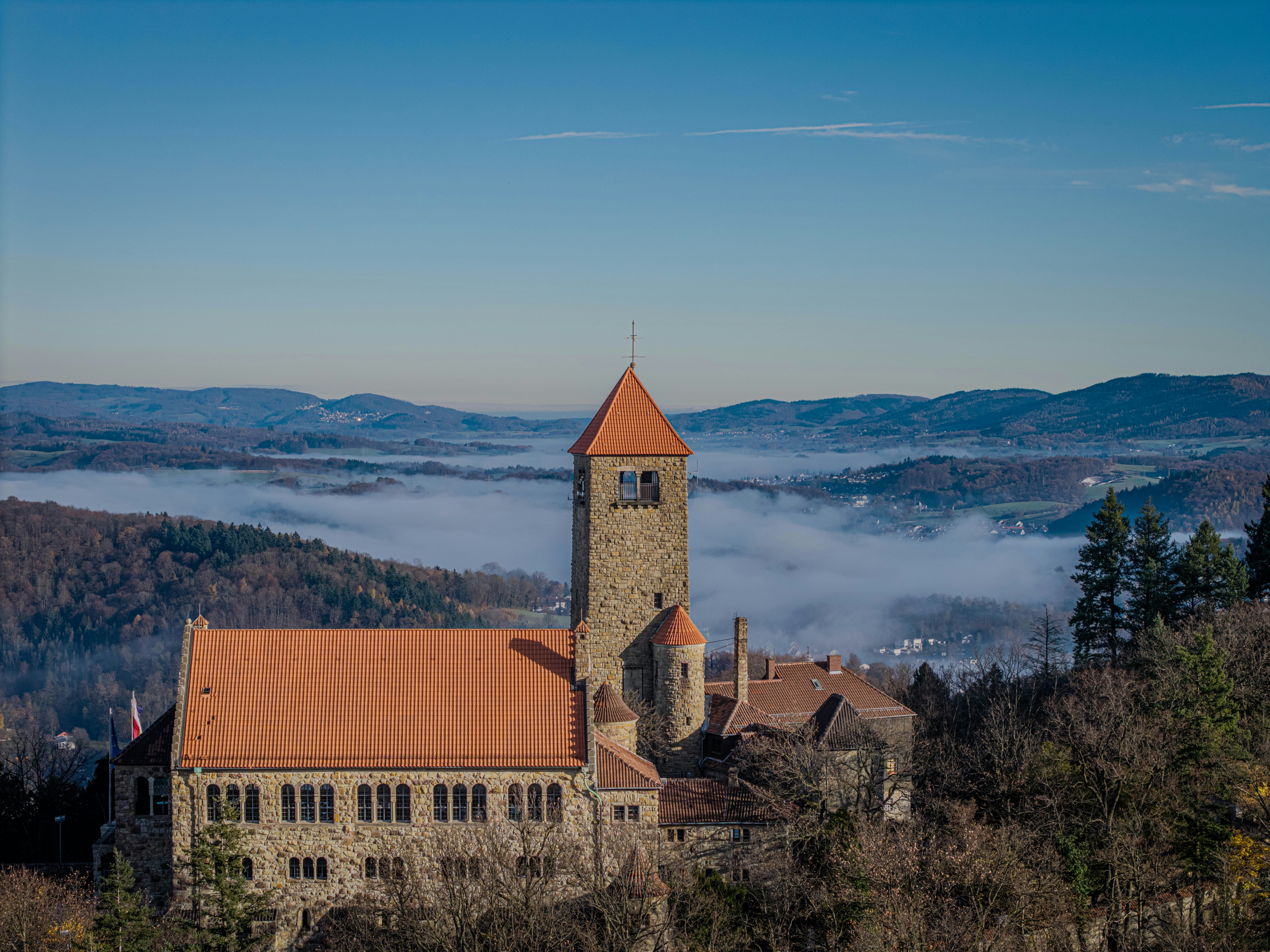 Mist-Guarded Fortress: Red-Topped Tower Above the Valley Fog