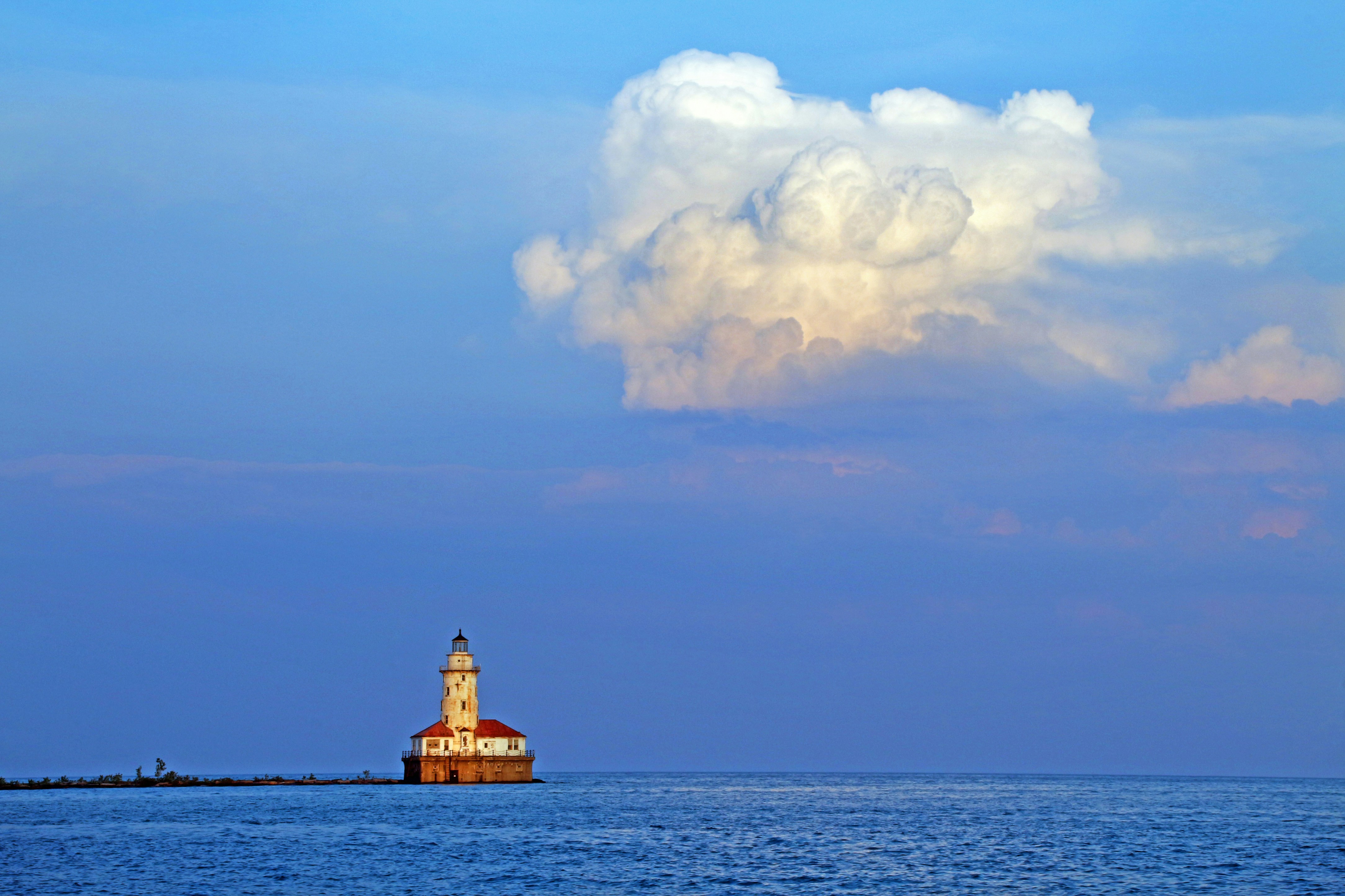 Beacon on the Blue Expanse: A Lone Lighthouse Standing Against a Calm Sea