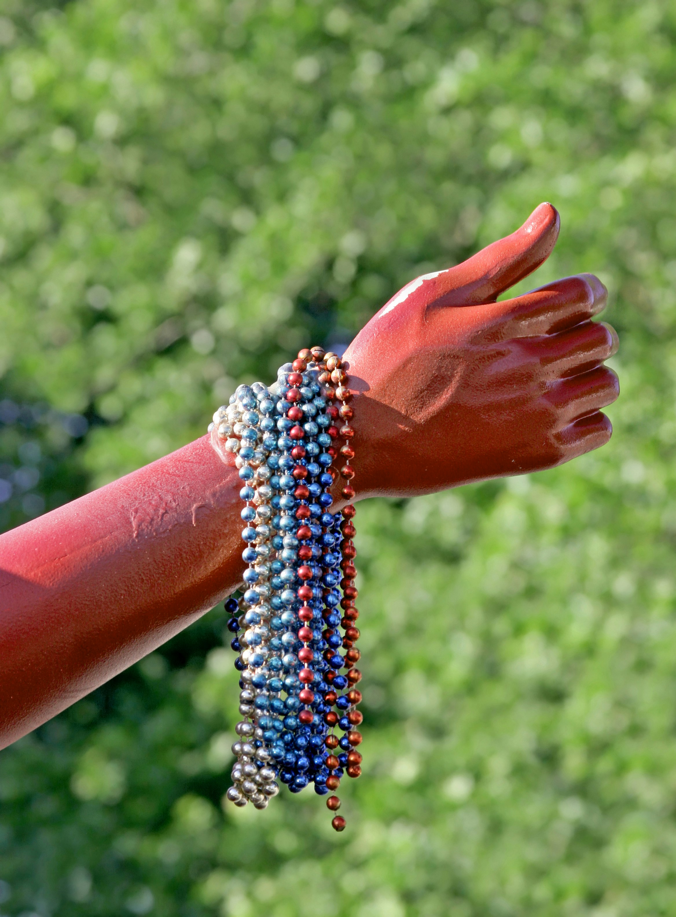 Prismatic Beads Draped on a Sunlit Arm Against Verdant Blur