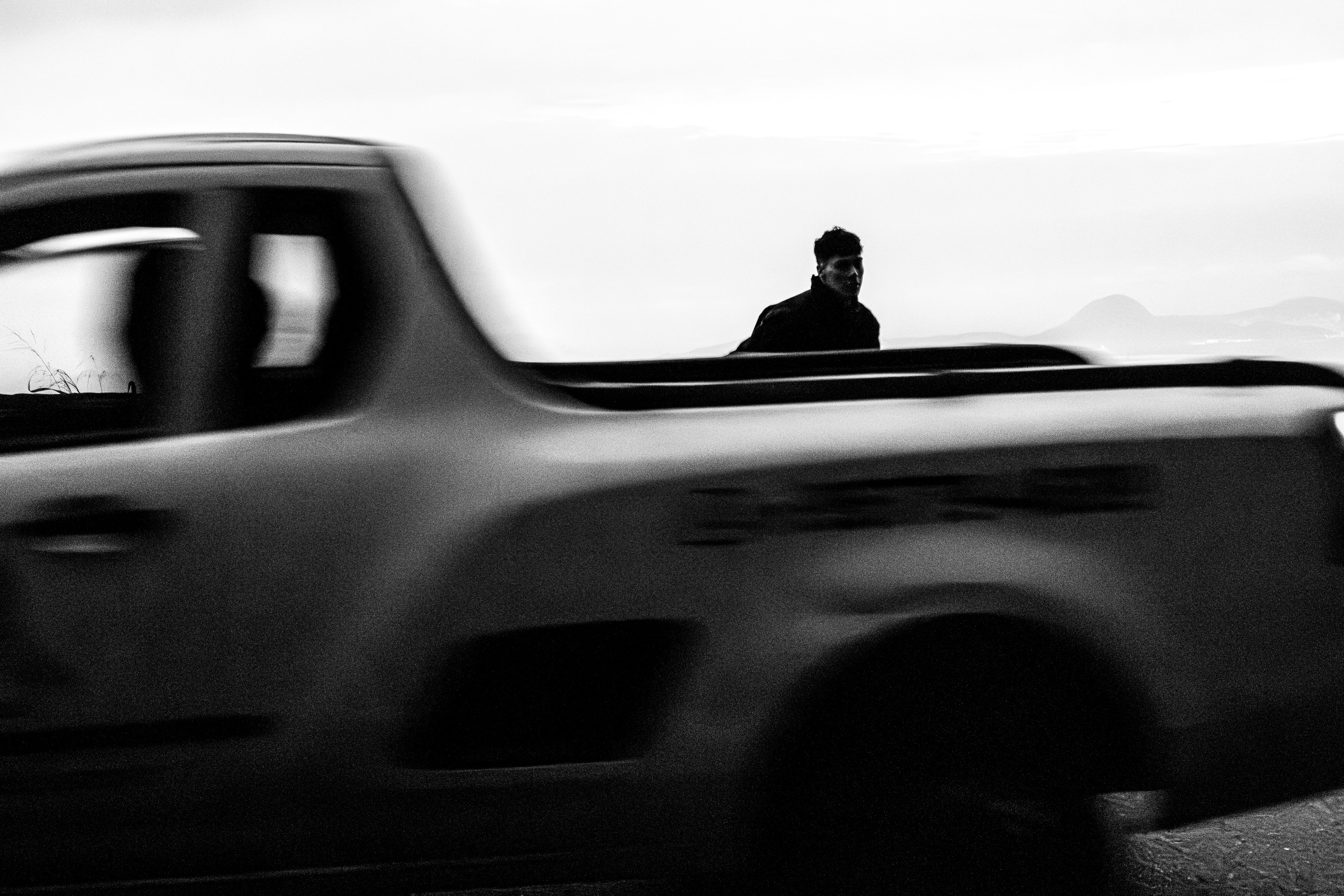 Silhouetted figure in blurred moving truck, a stark, grainy, fleeting journey.
