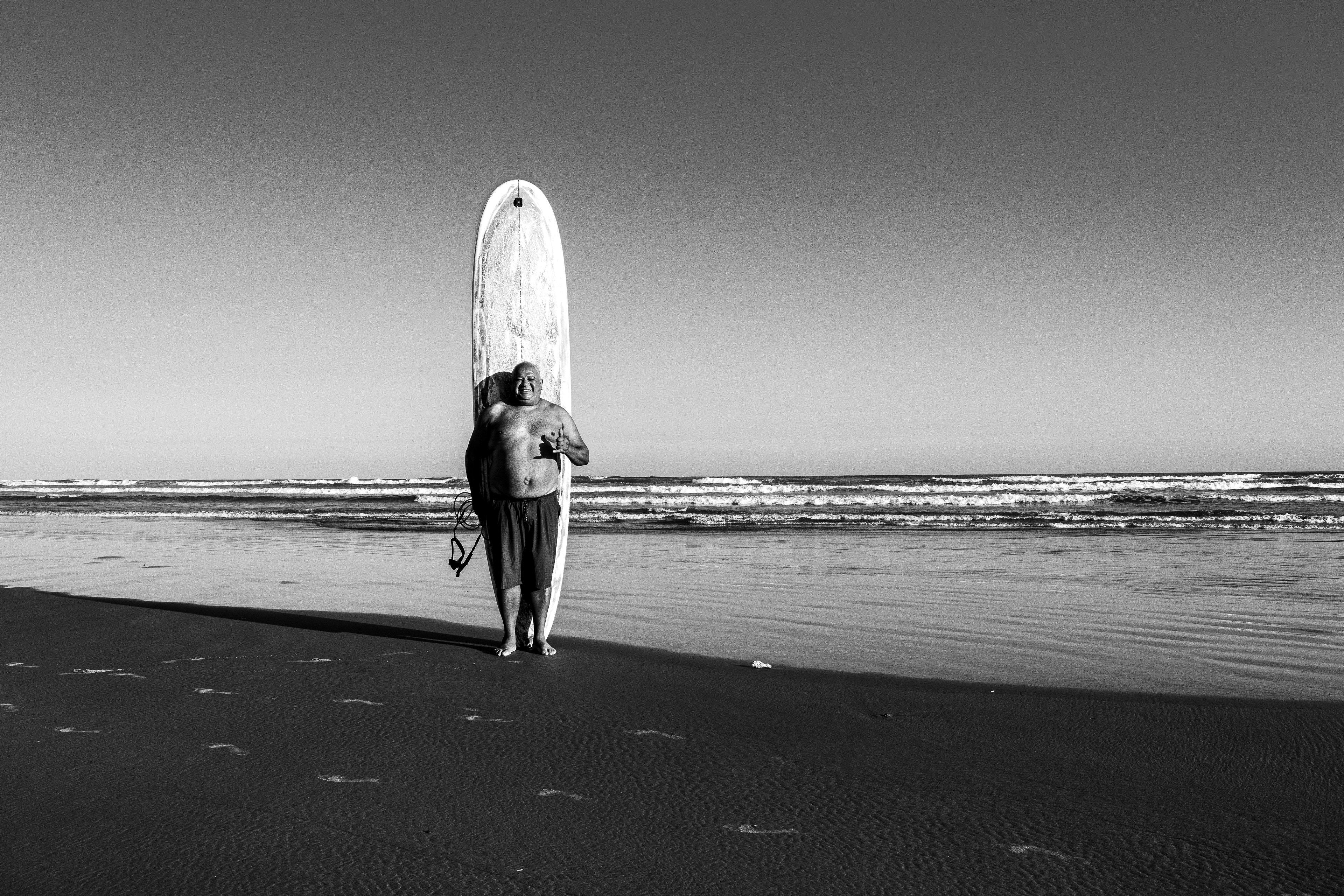 Grayscale Quiet: A Surfer's Gentle Embrace by the Shore