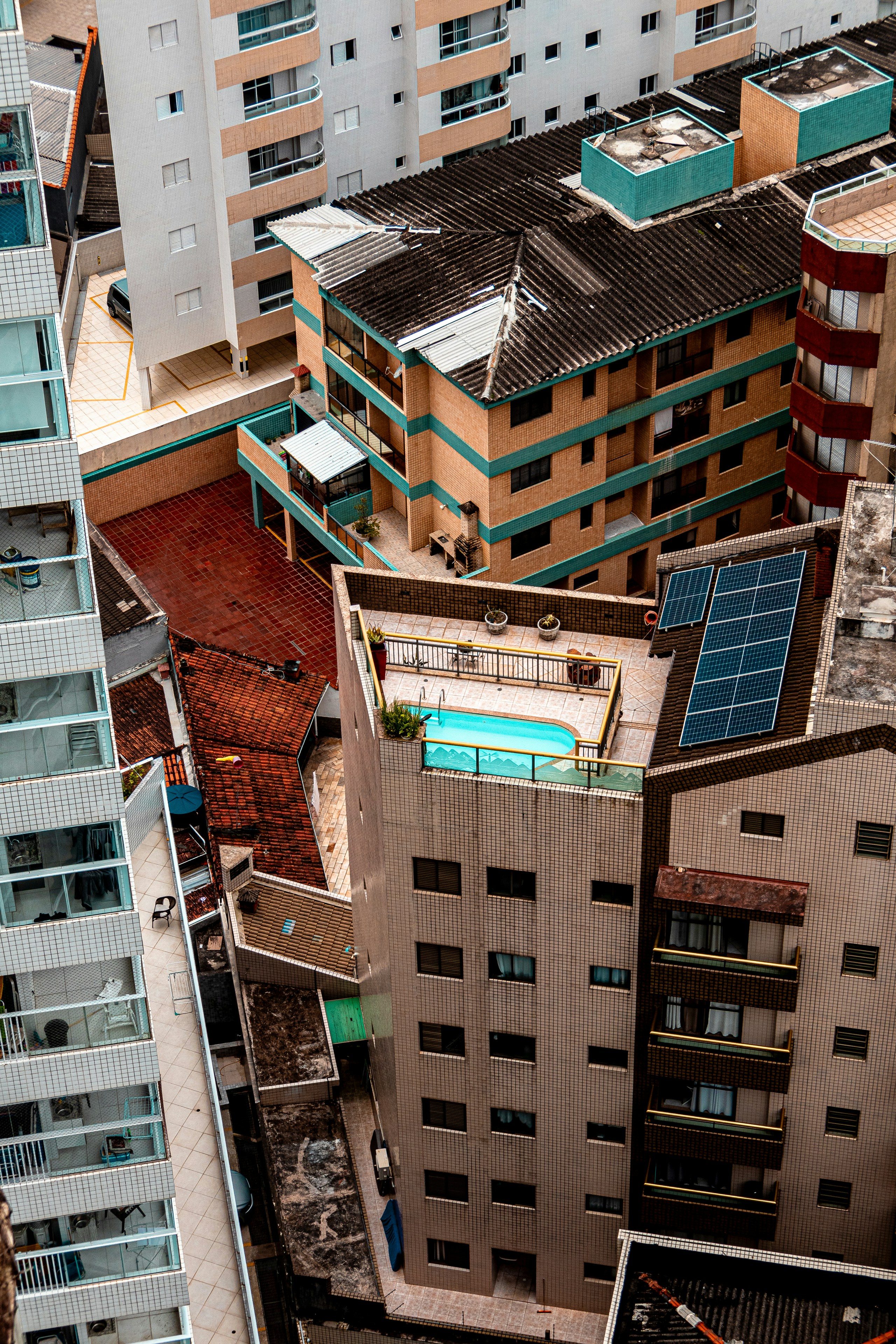 Dense urban landscape reveals rooftop pool, solar panels, and varied architecture.