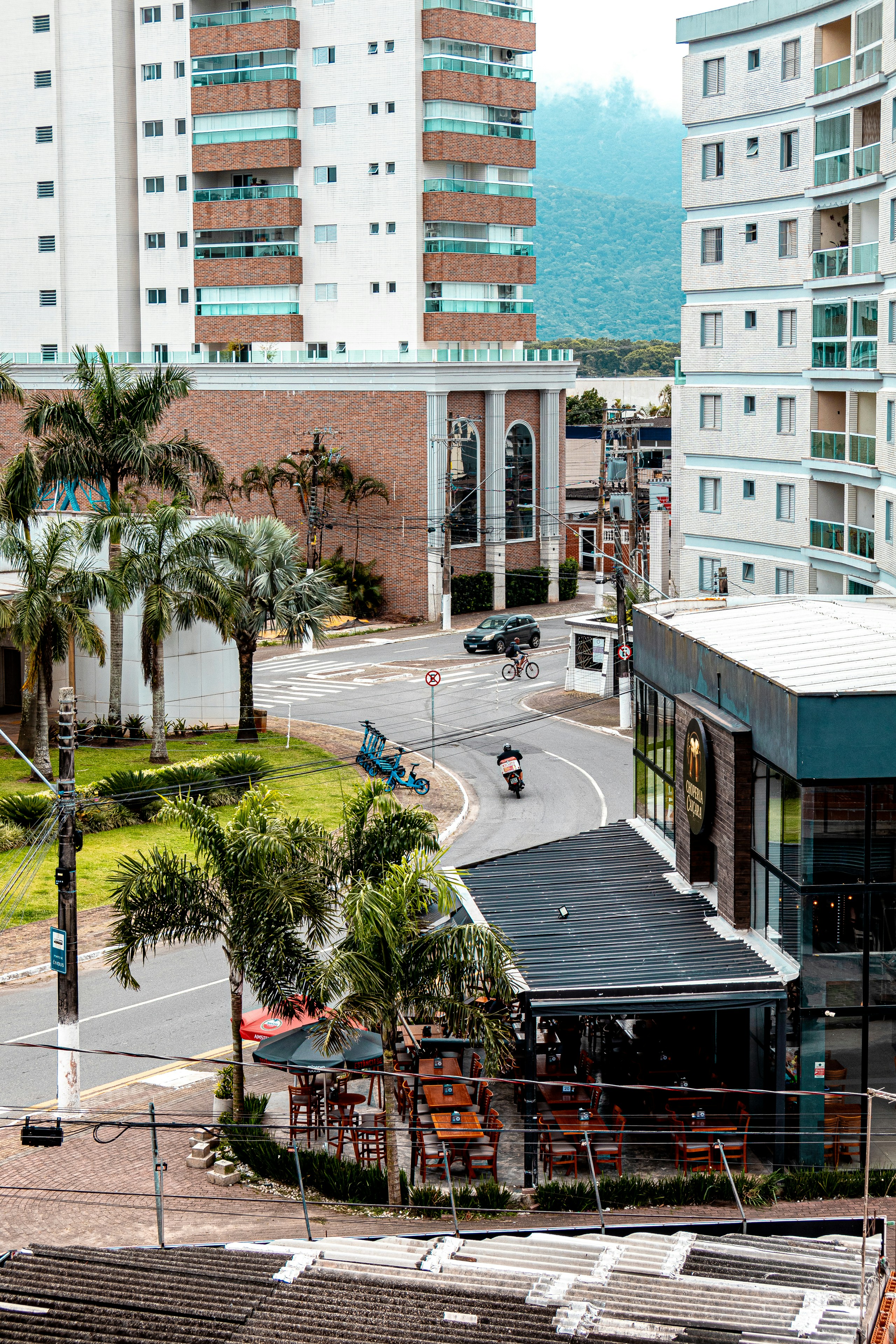 Elevated view of a bustling street, tropical city charm, mountain backdrop.