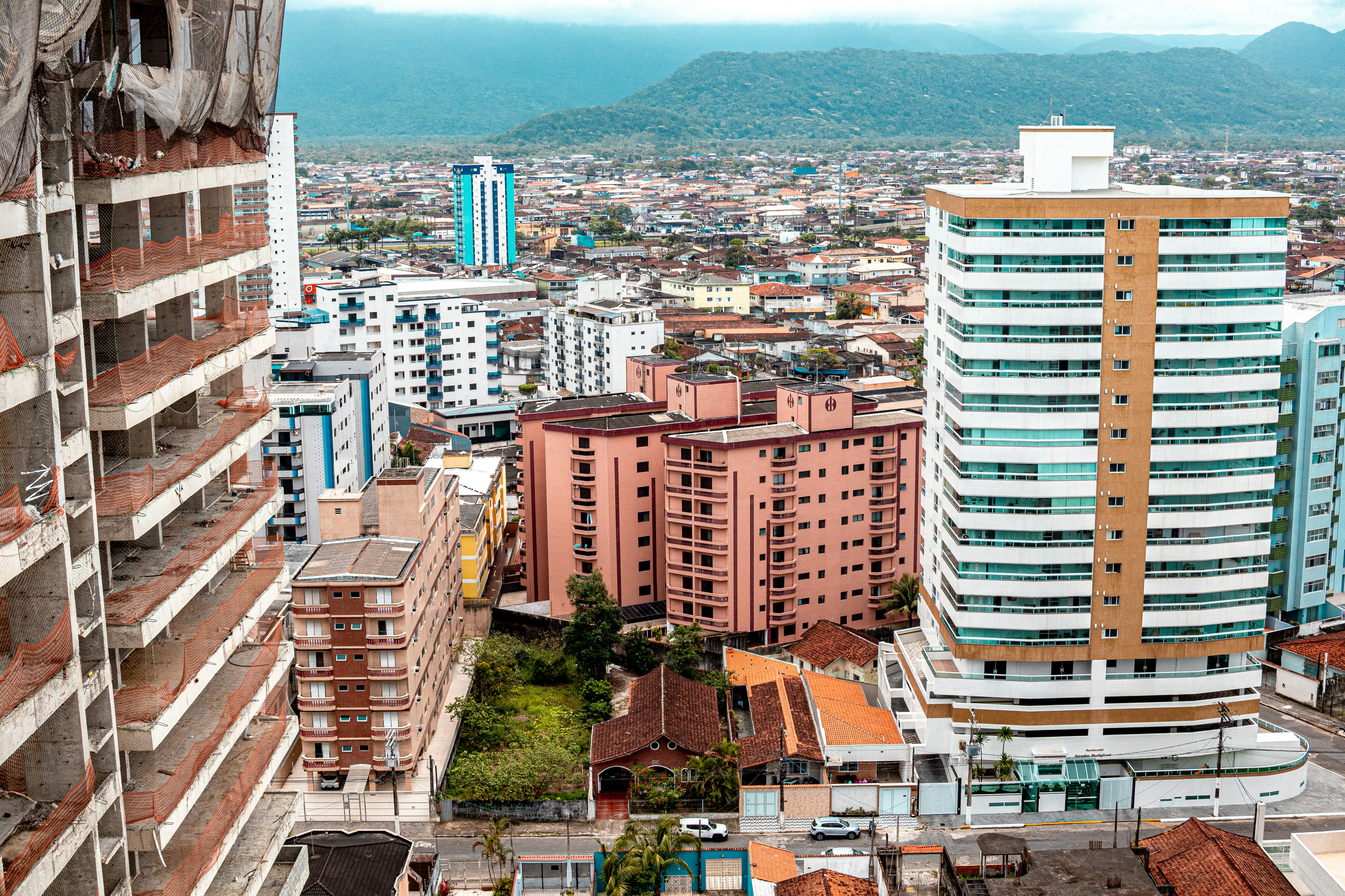 A vibrant city evolving, embraced by serene, mist-shrouded green mountains.