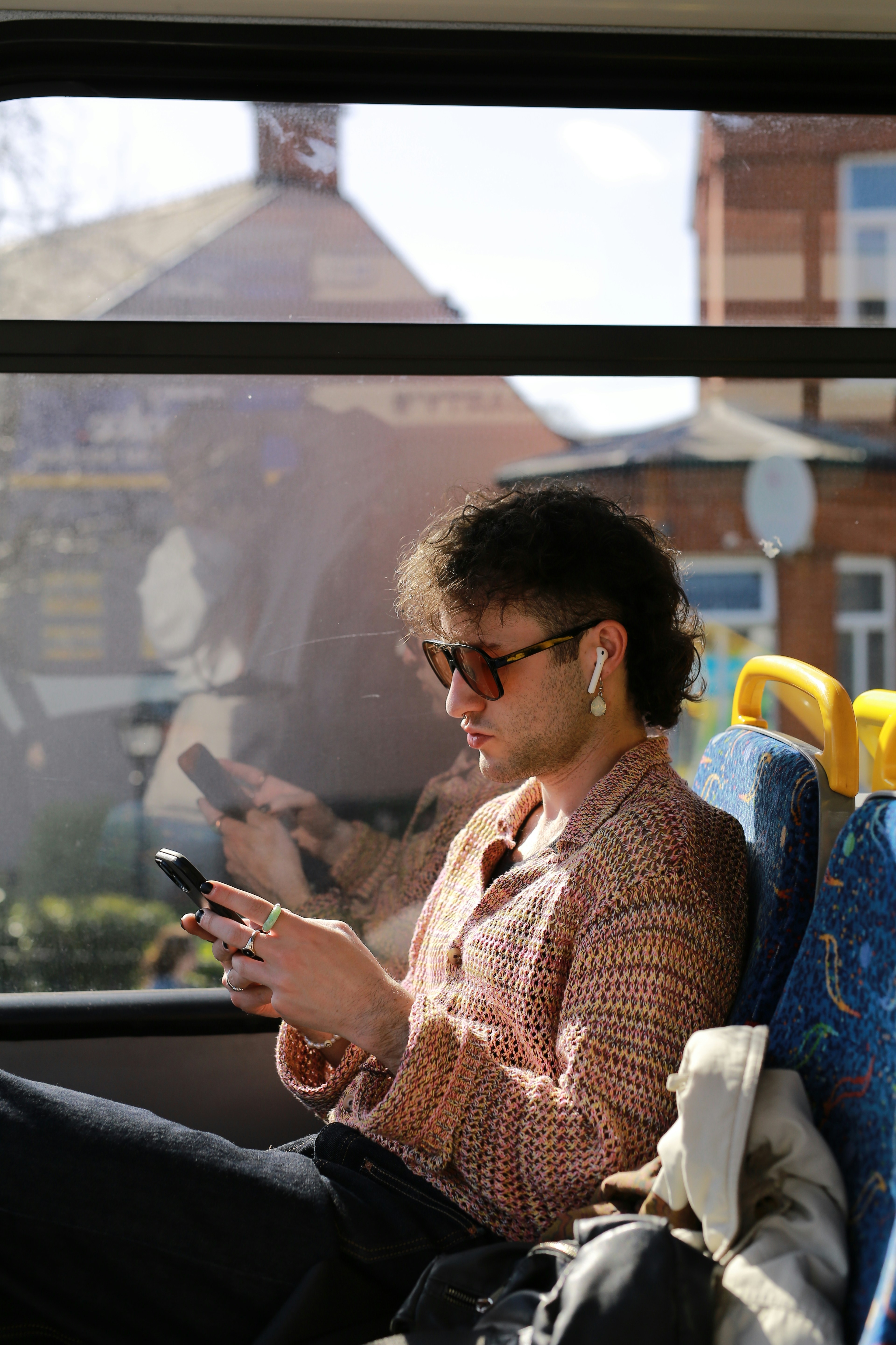 Sunlit Commute: A Quiet Moment with a Phone on the City Bus