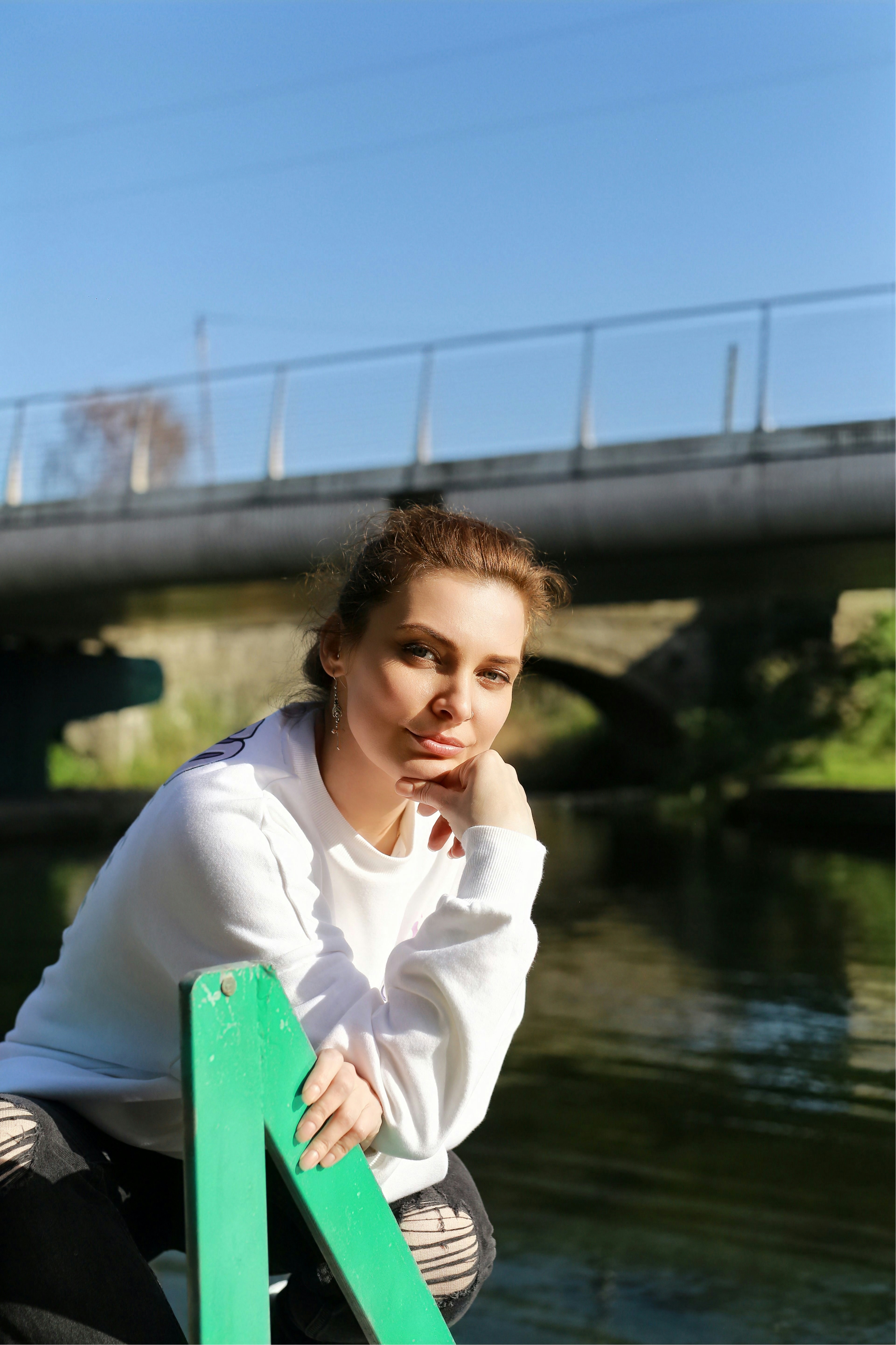 Sunlit Contemplation by the Riverside Green Railing