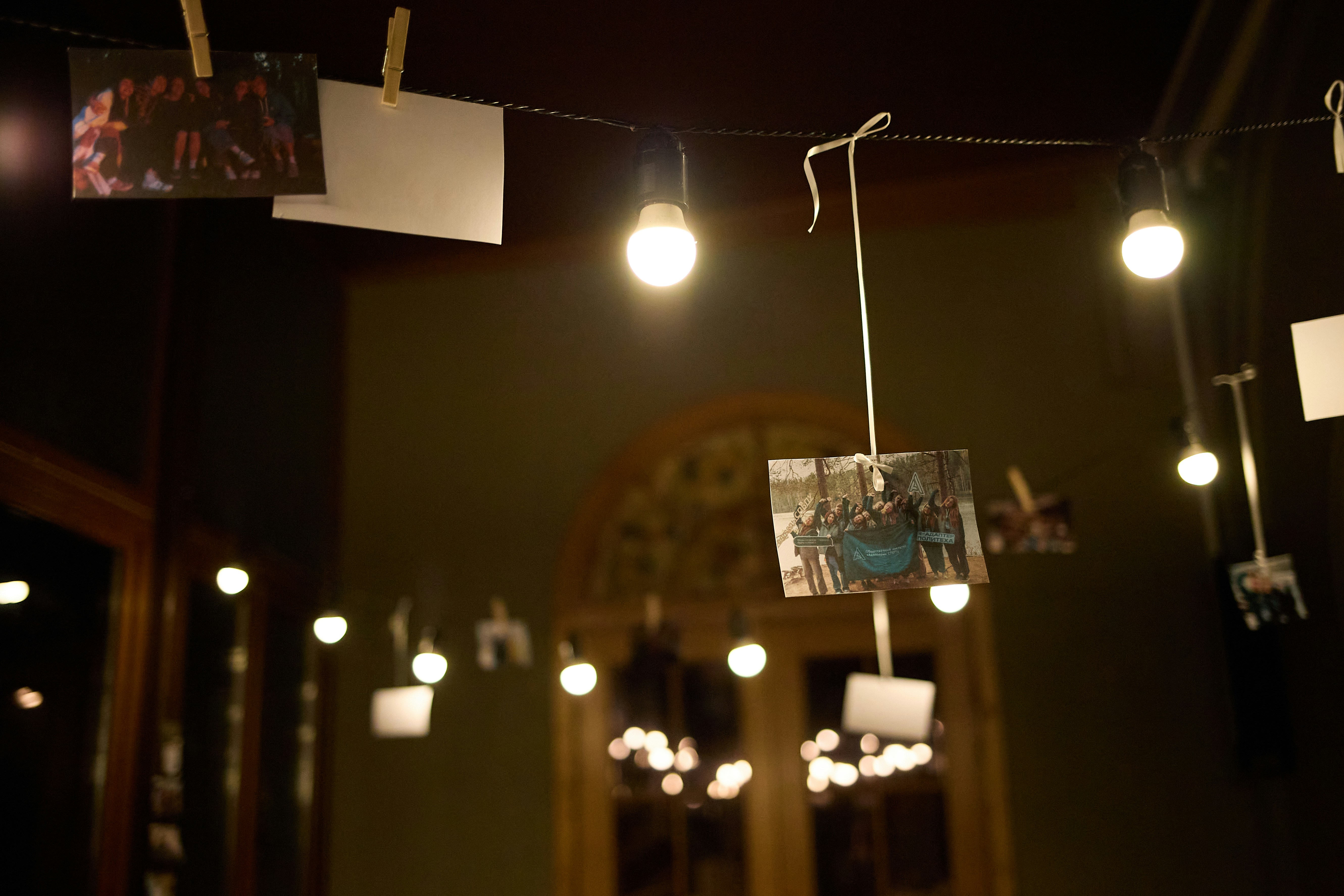 Strings of Small Portraits Under Warm Orbs in a Velvet Hall