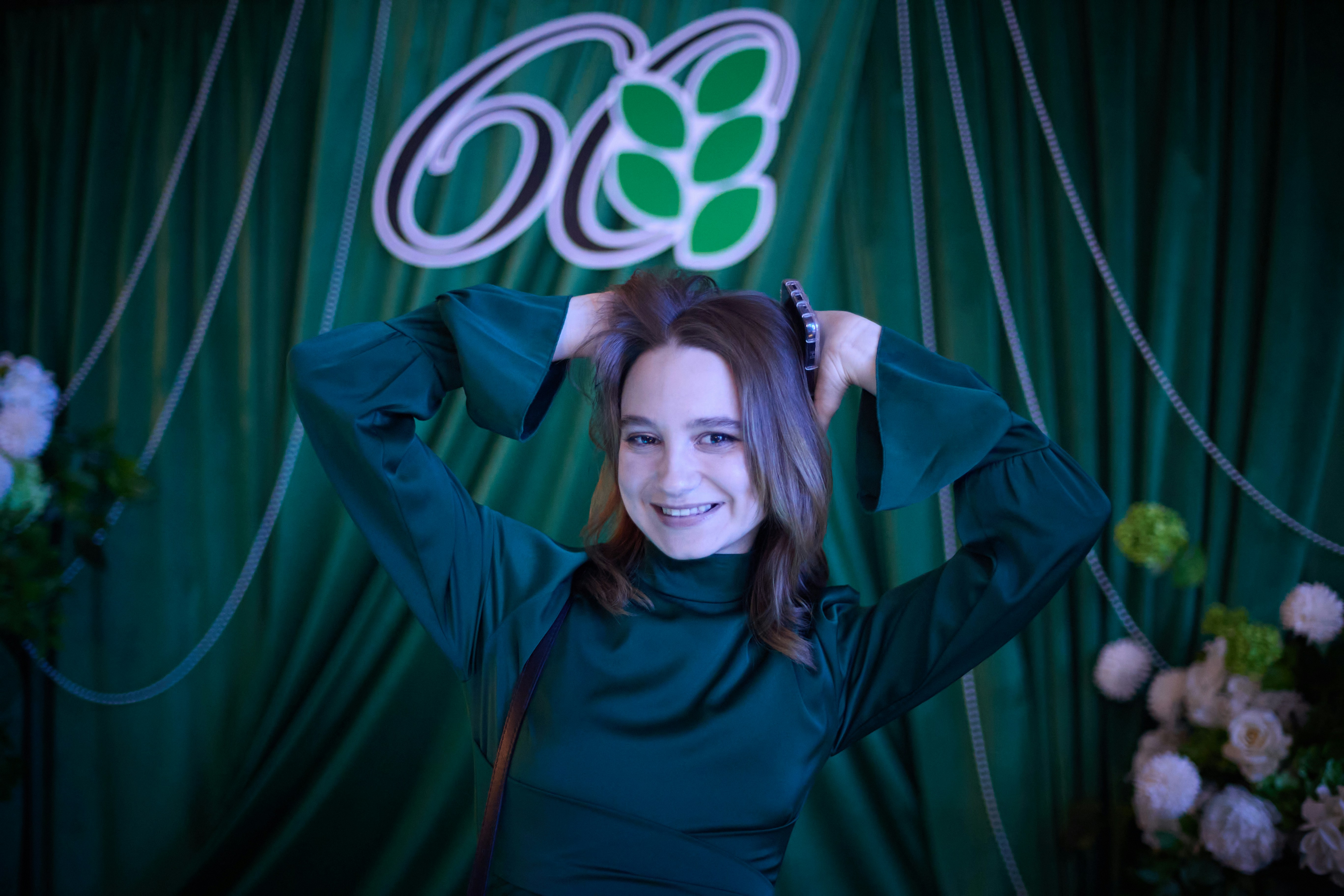 Emerald Curtain Portrait: A Jubilant Pose Under a Leaf-Emblem Backdrop
