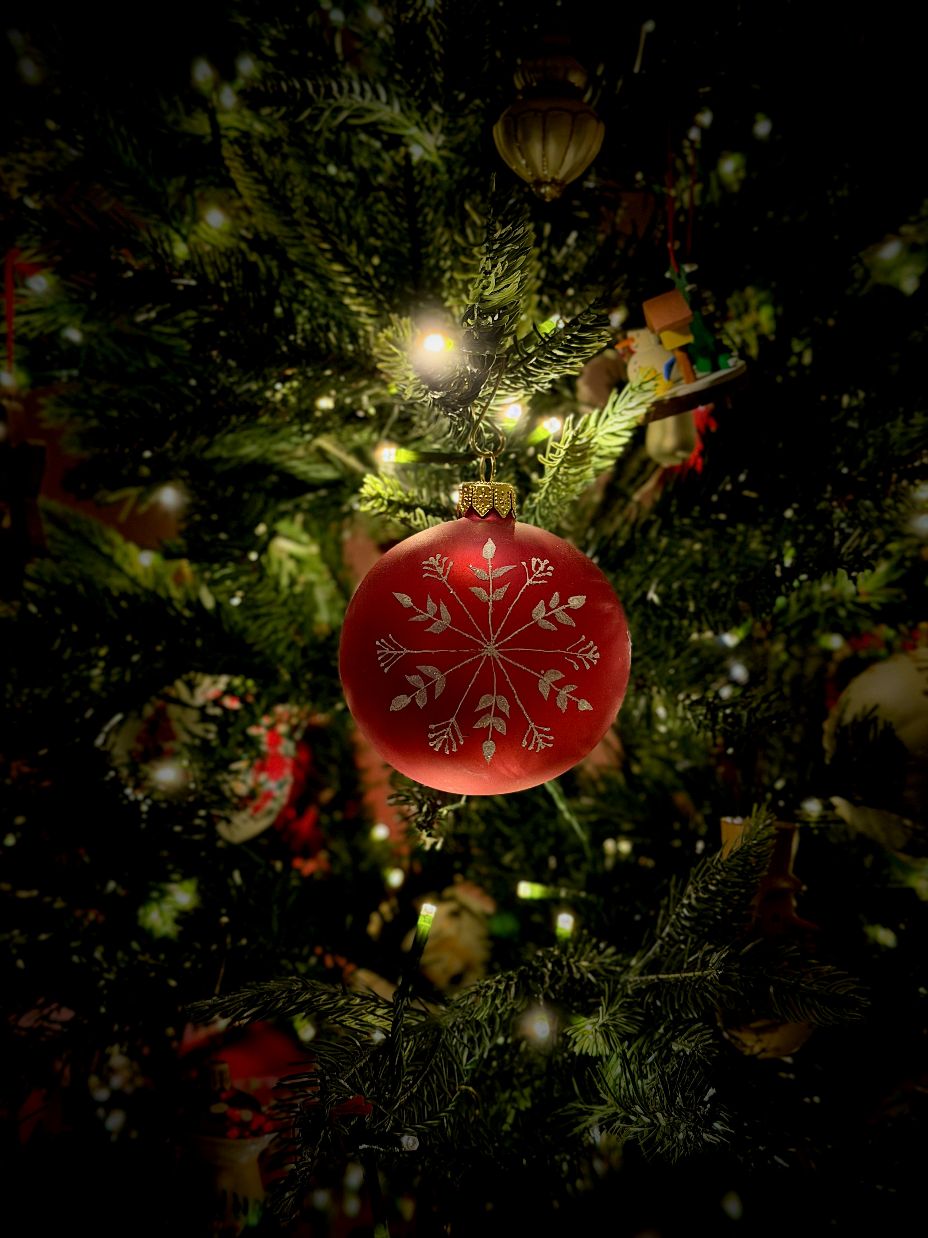 Red ornament with snowflake design on christmas tree.