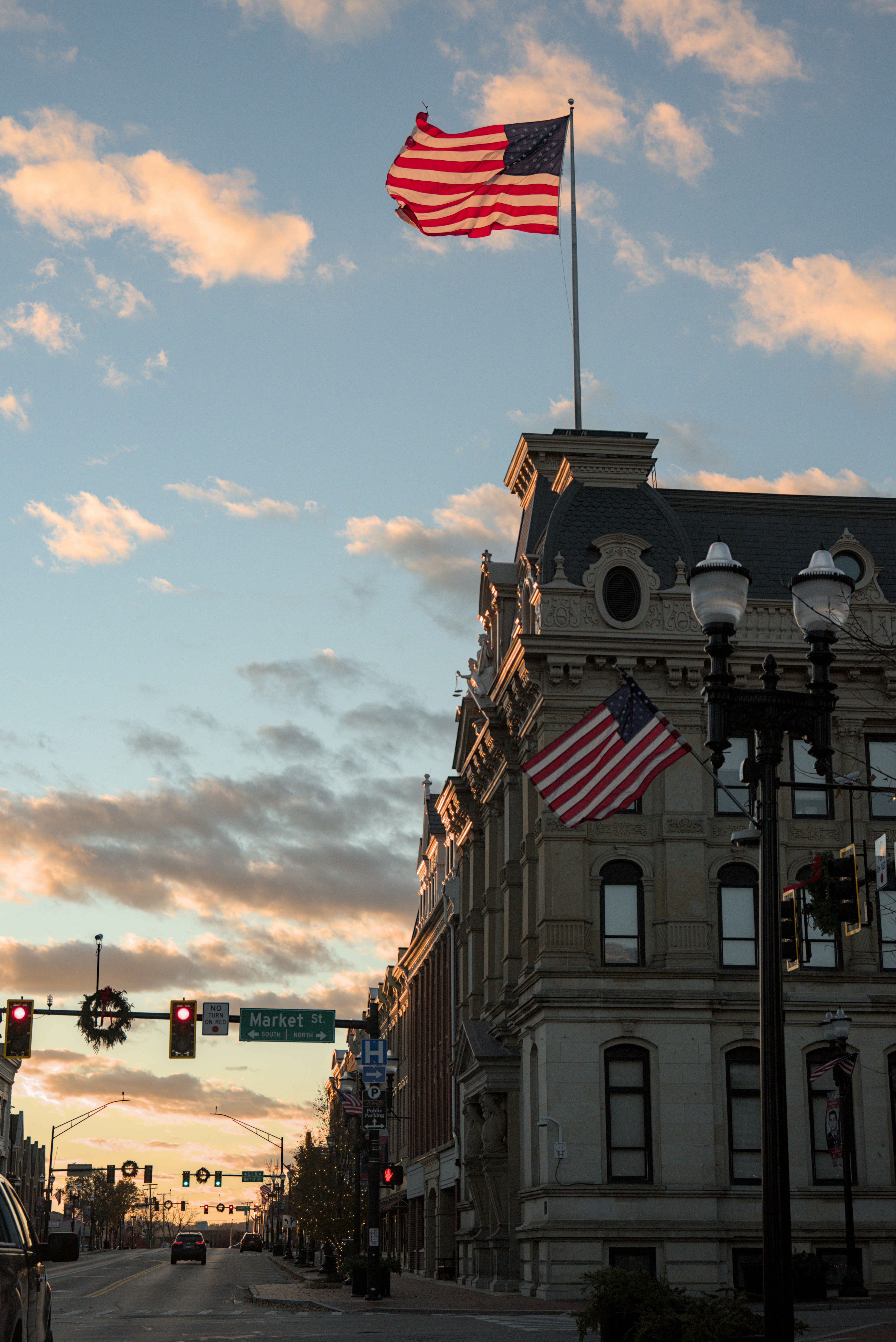 Flag-Crowned Beaux-Arts Corner at Dusk: Flags, Lanterns, and a Quiet Downtown Street