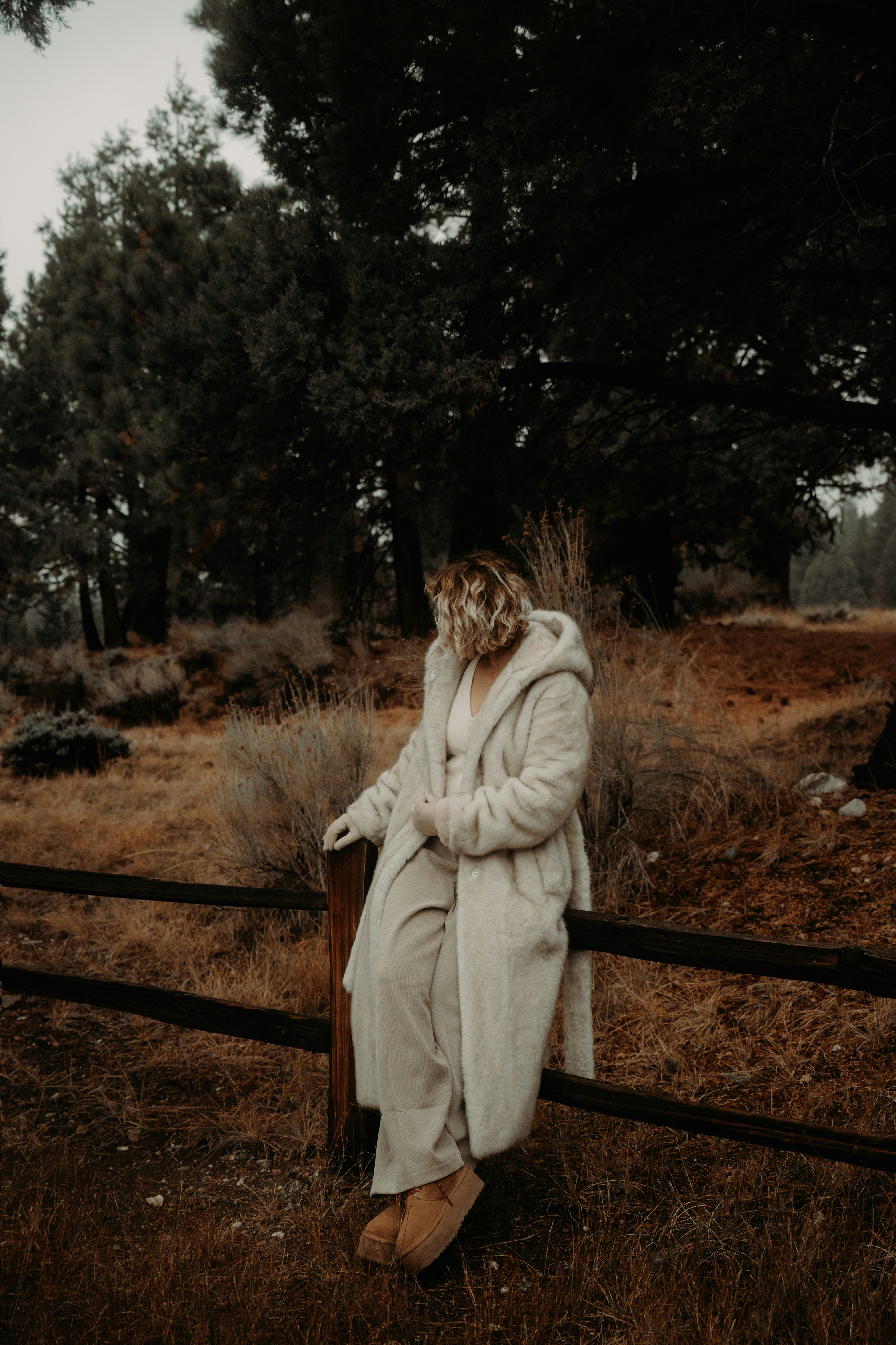Woman sitting on wooden fence in autumnal landscape