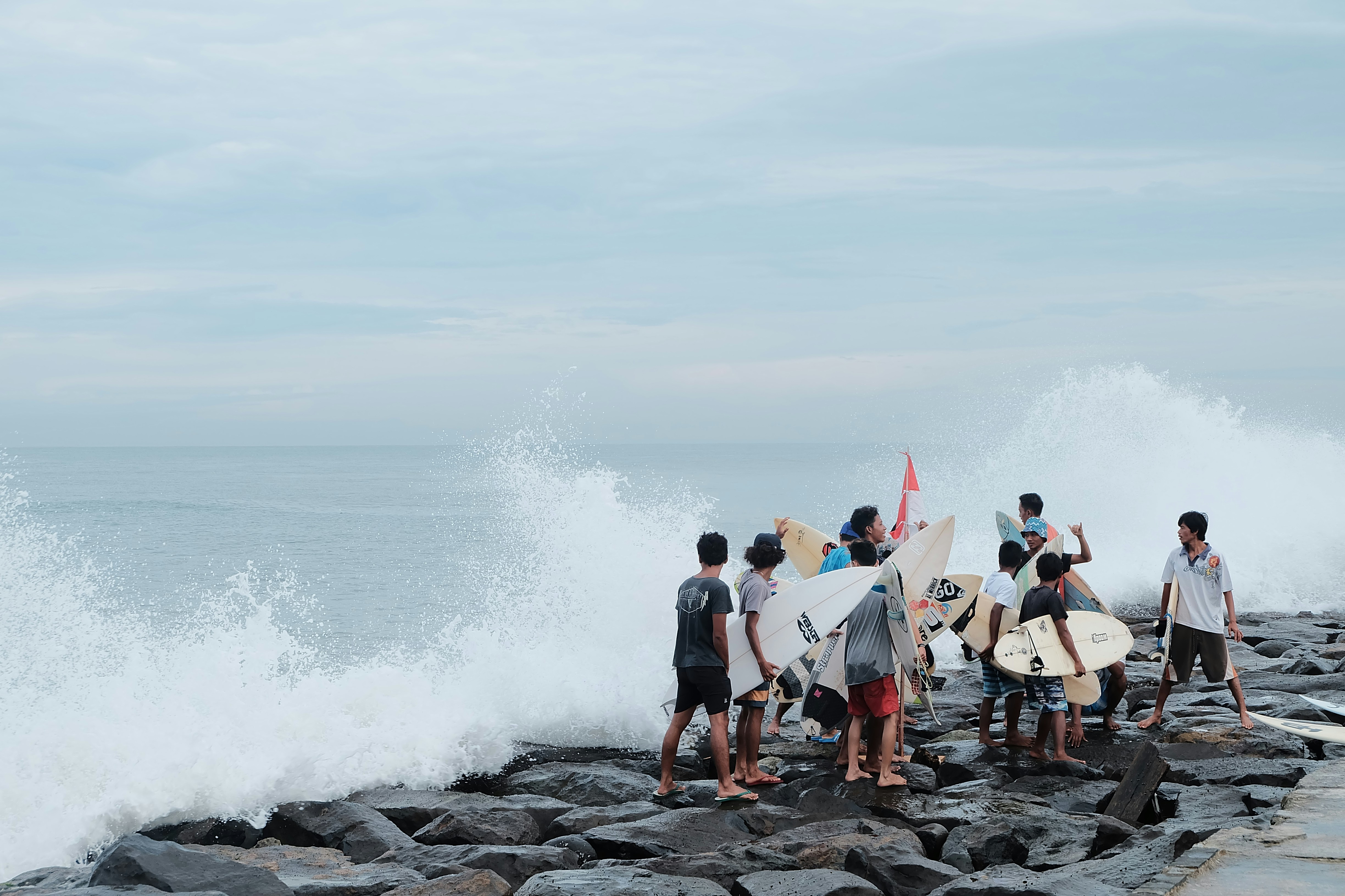 Breakwater Assembly: Surfers Gather as White Spray Darts the Rocks