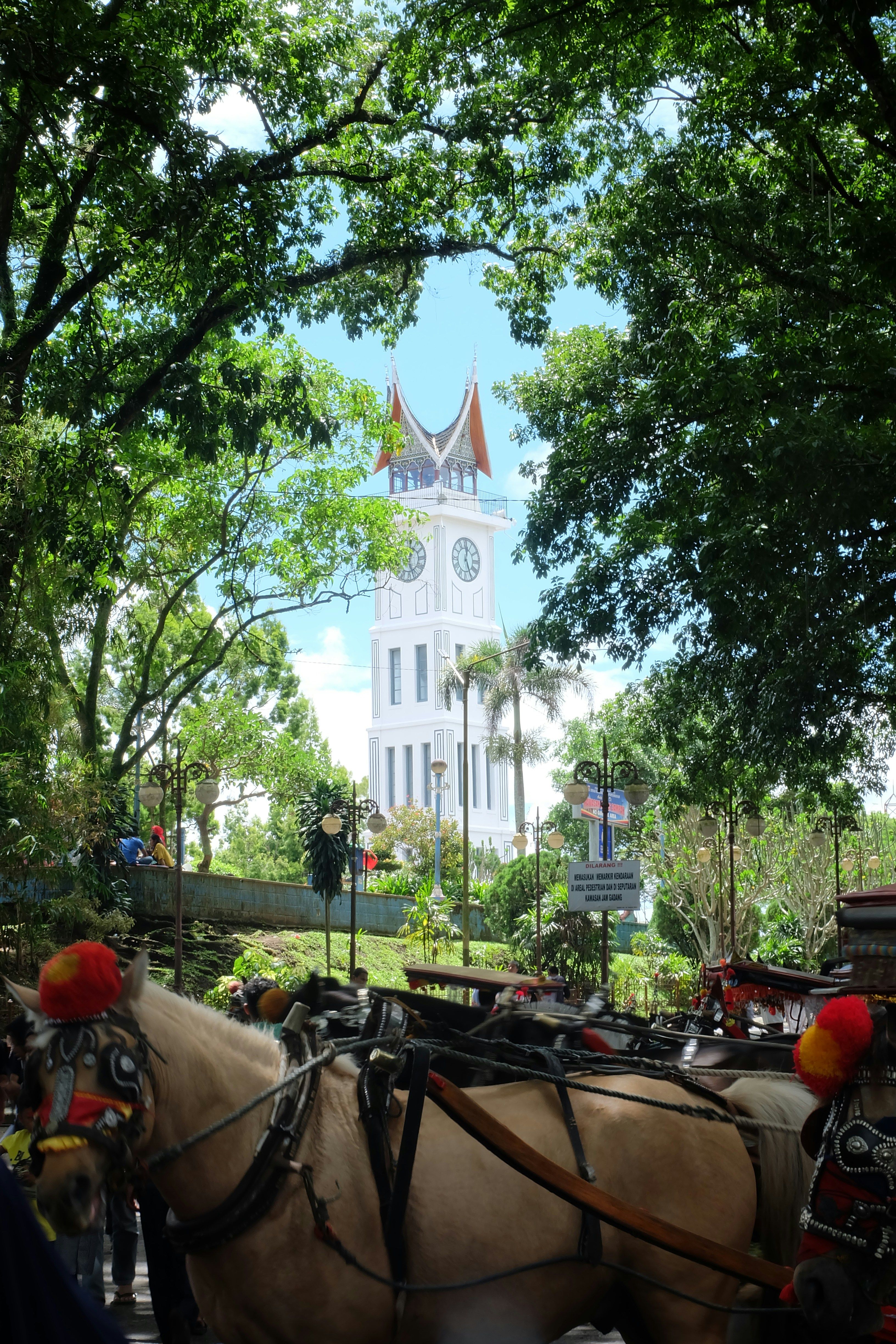 Clock Tower in a Green Cathedral: Horse-Drawn Scene Framed by Trees