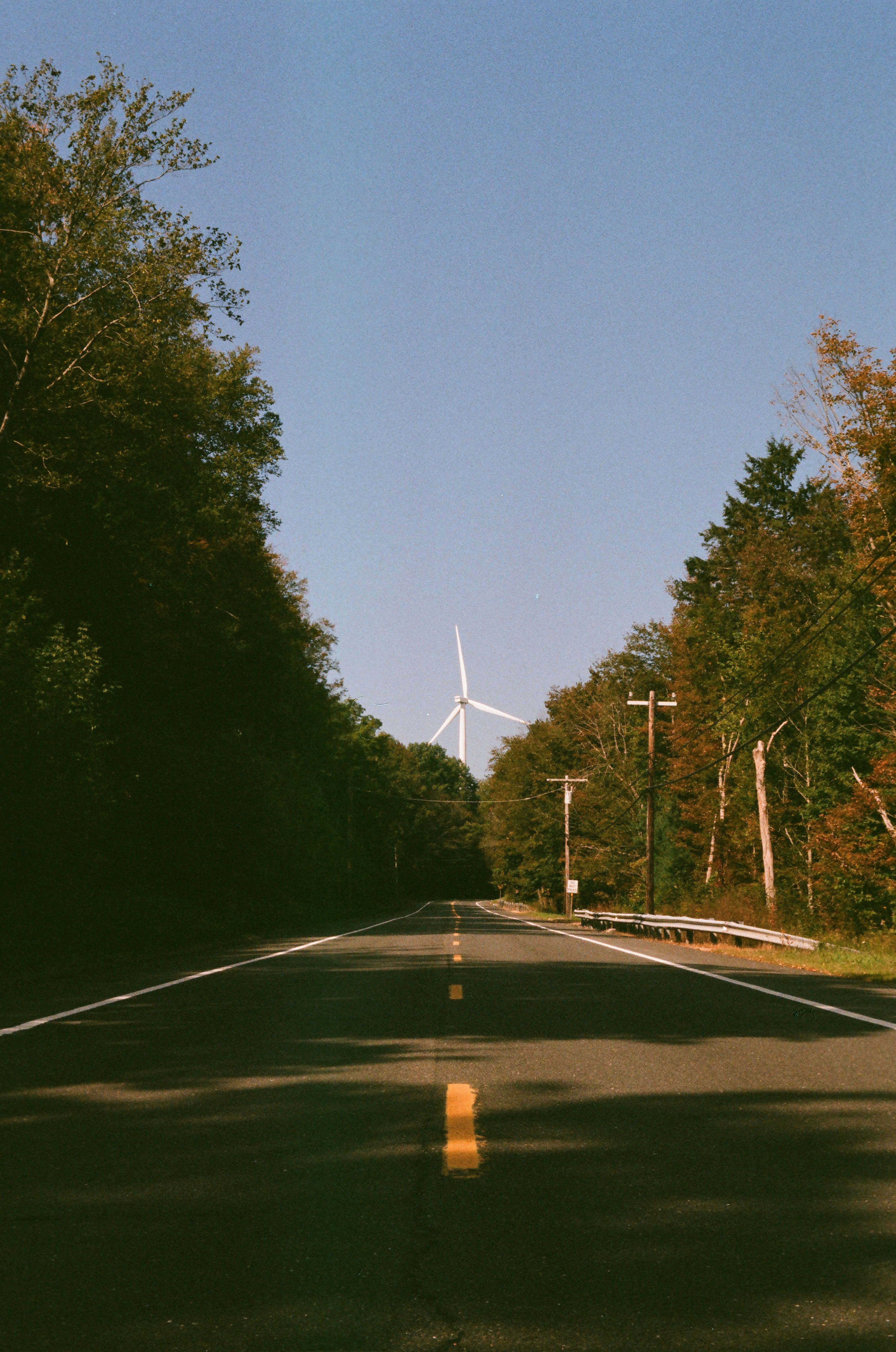 A road leads to a distant wind turbine. photo – Free Travel Image on ...