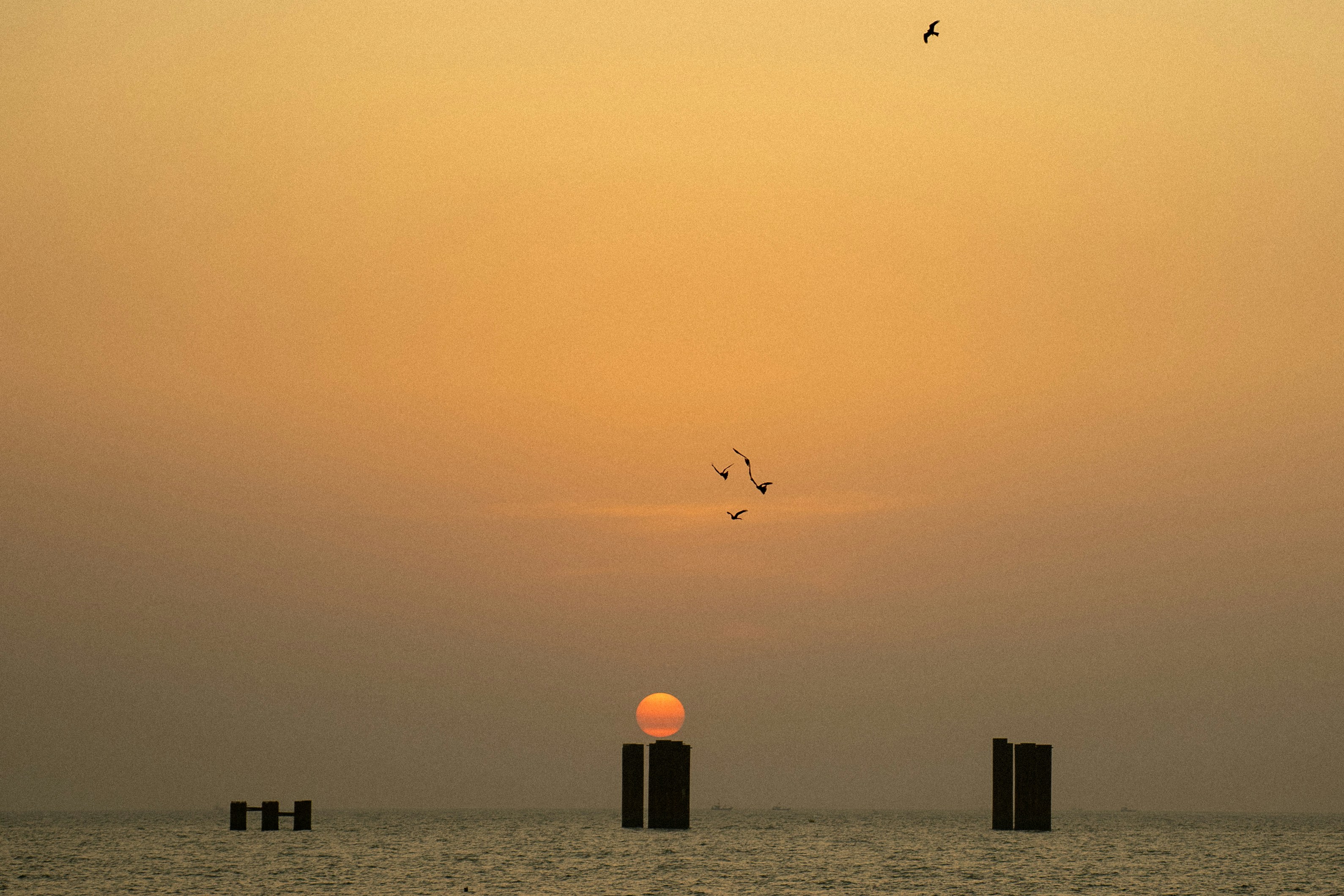Sunset Balance: a sun perched on a lone pilaster amid sea-posts