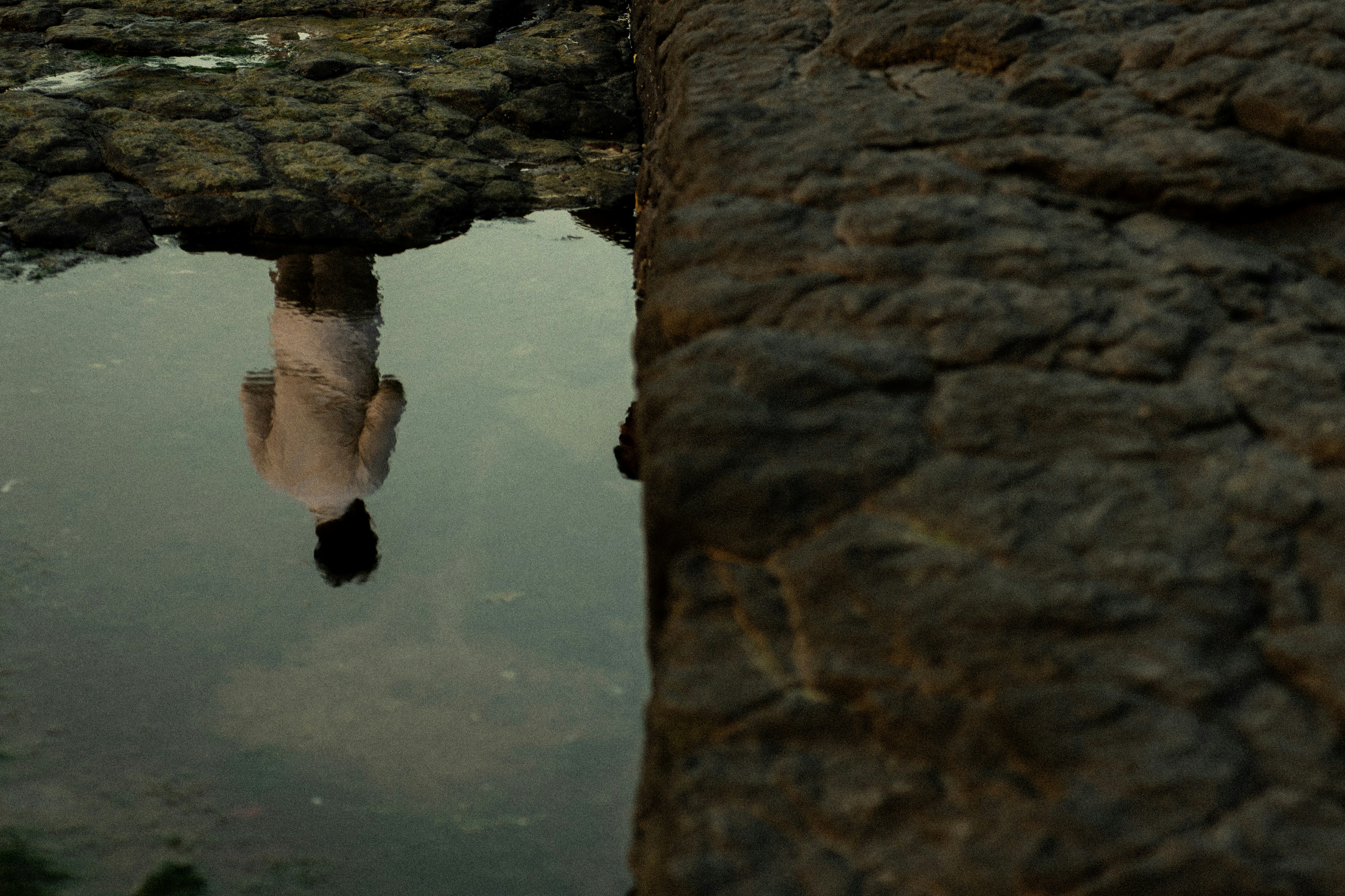 Inverted Silhouette in a Quiet Tide Pool Between Weathered Rocks