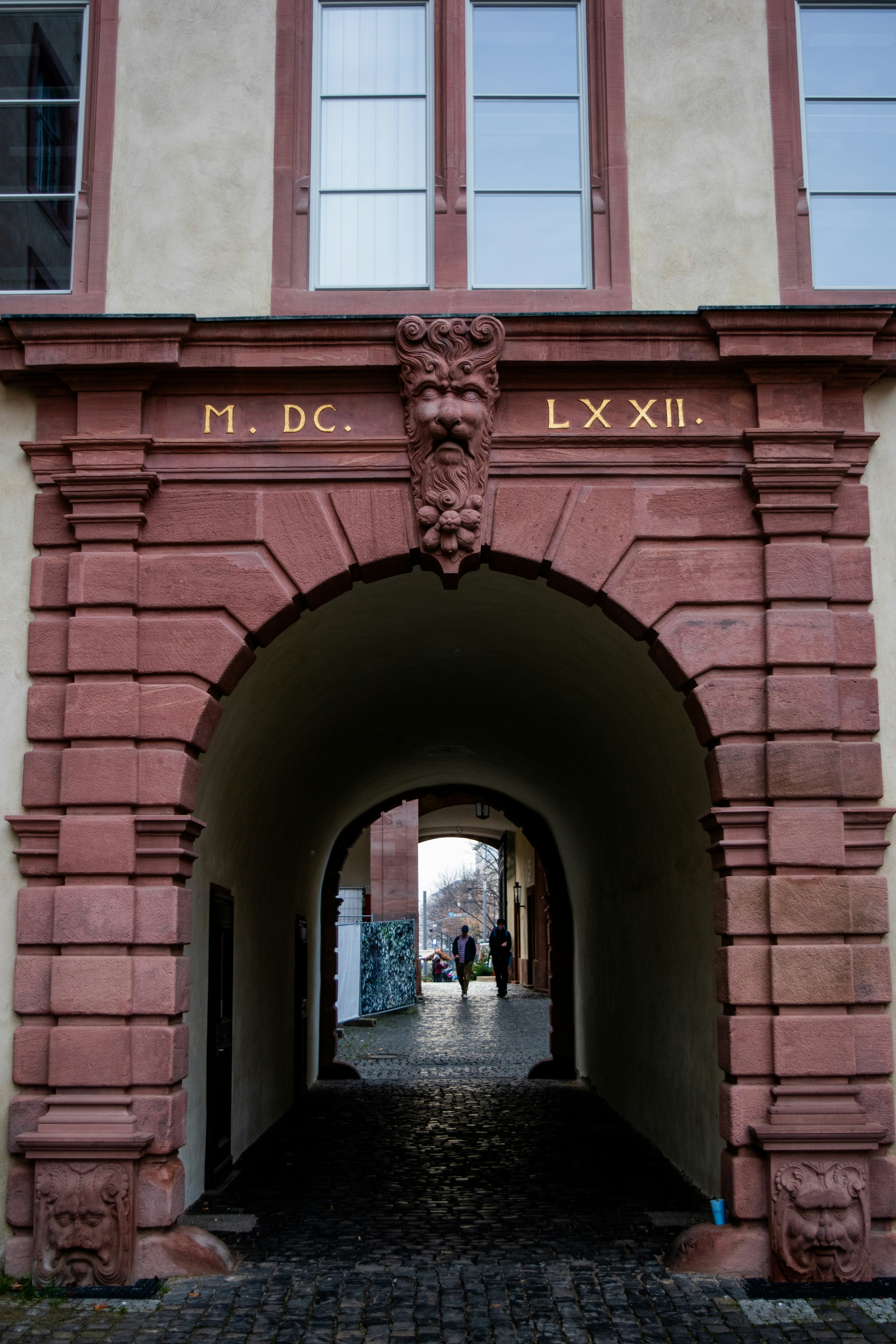 Portal of the Lion-Keystone: Cobblestone Corridor Through a Red Arch